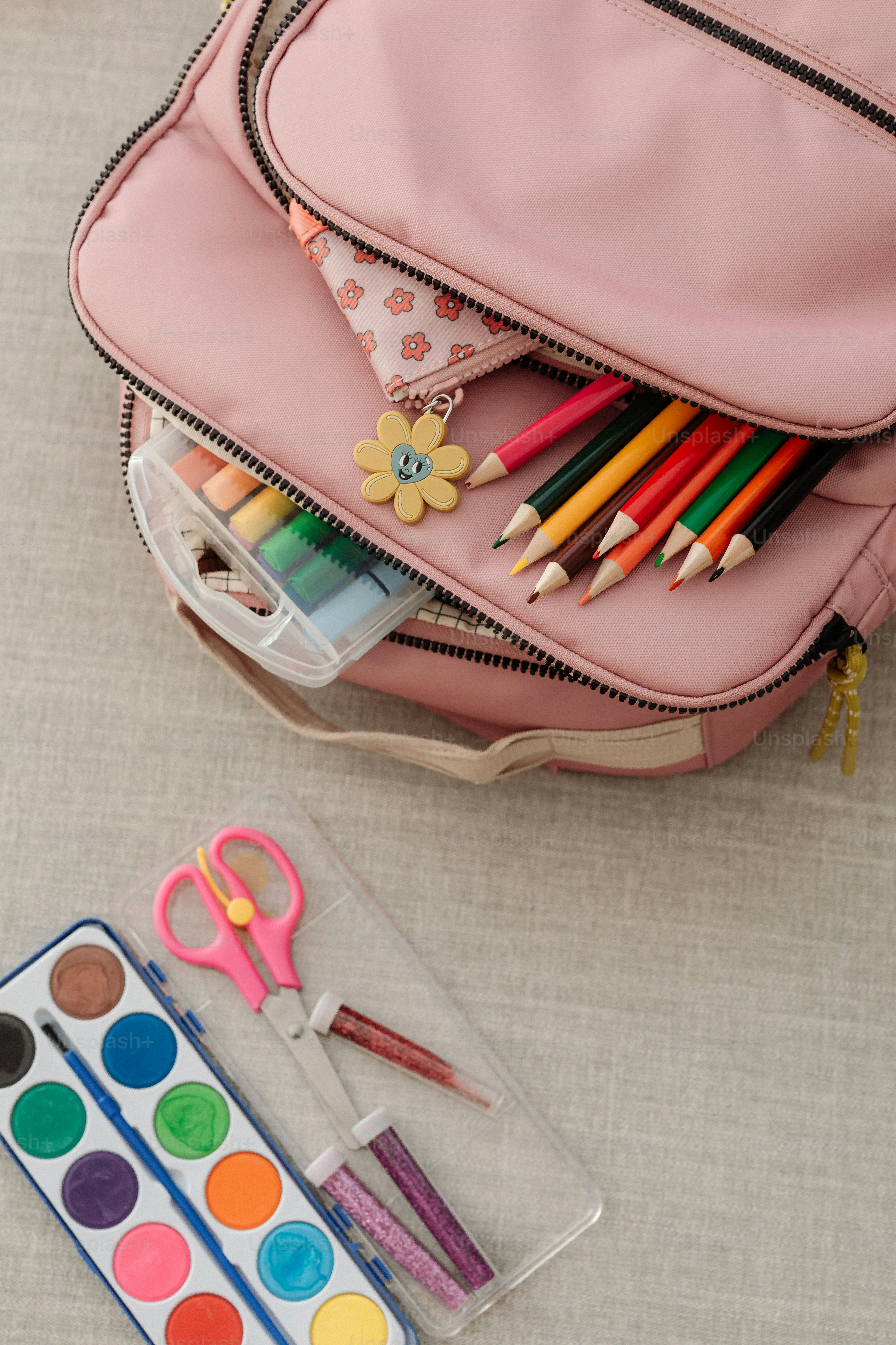 A pink backpack filled with markers, pencils, and markers photo ...