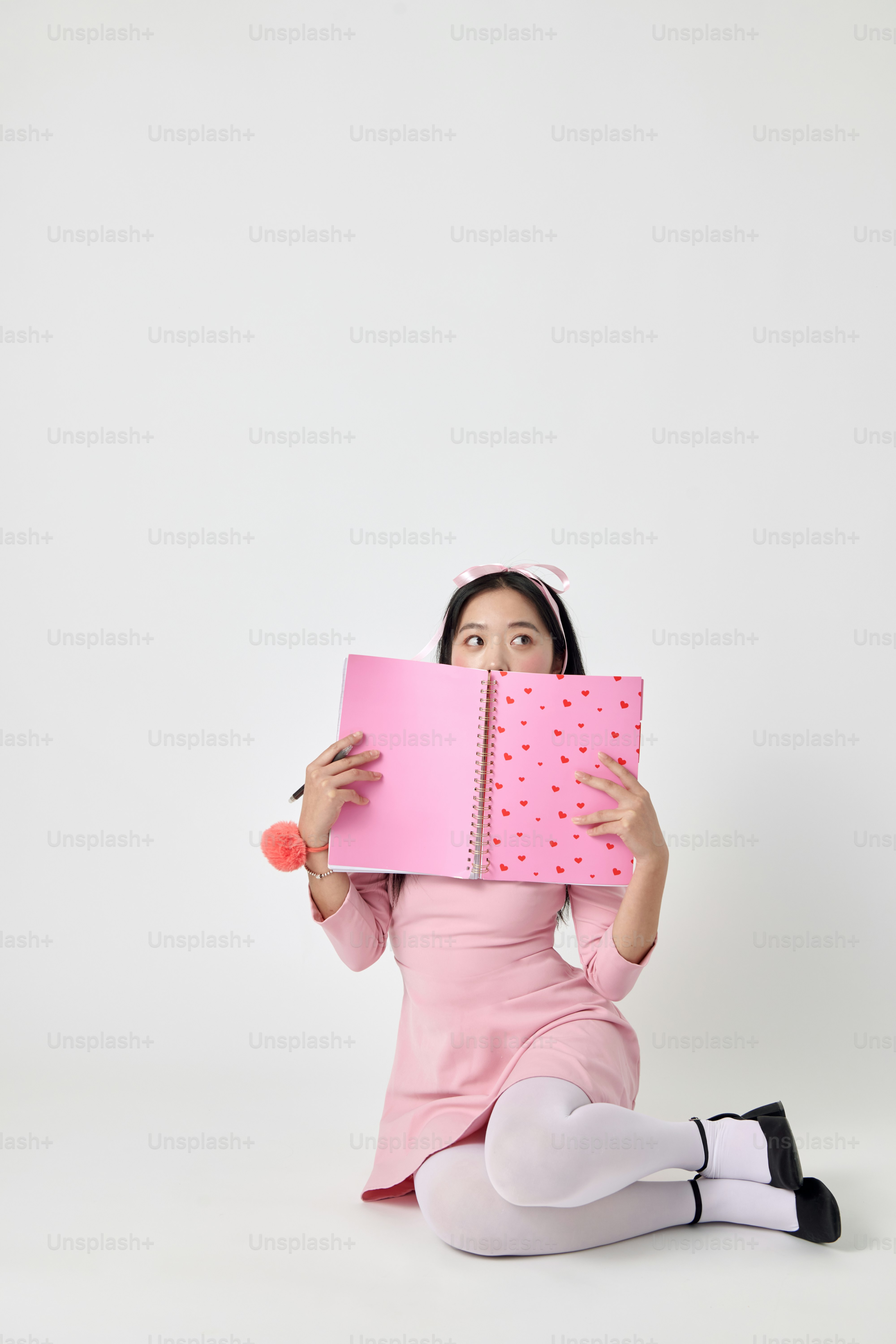 A woman sitting on the floor holding a pink book photo – Young woman ...