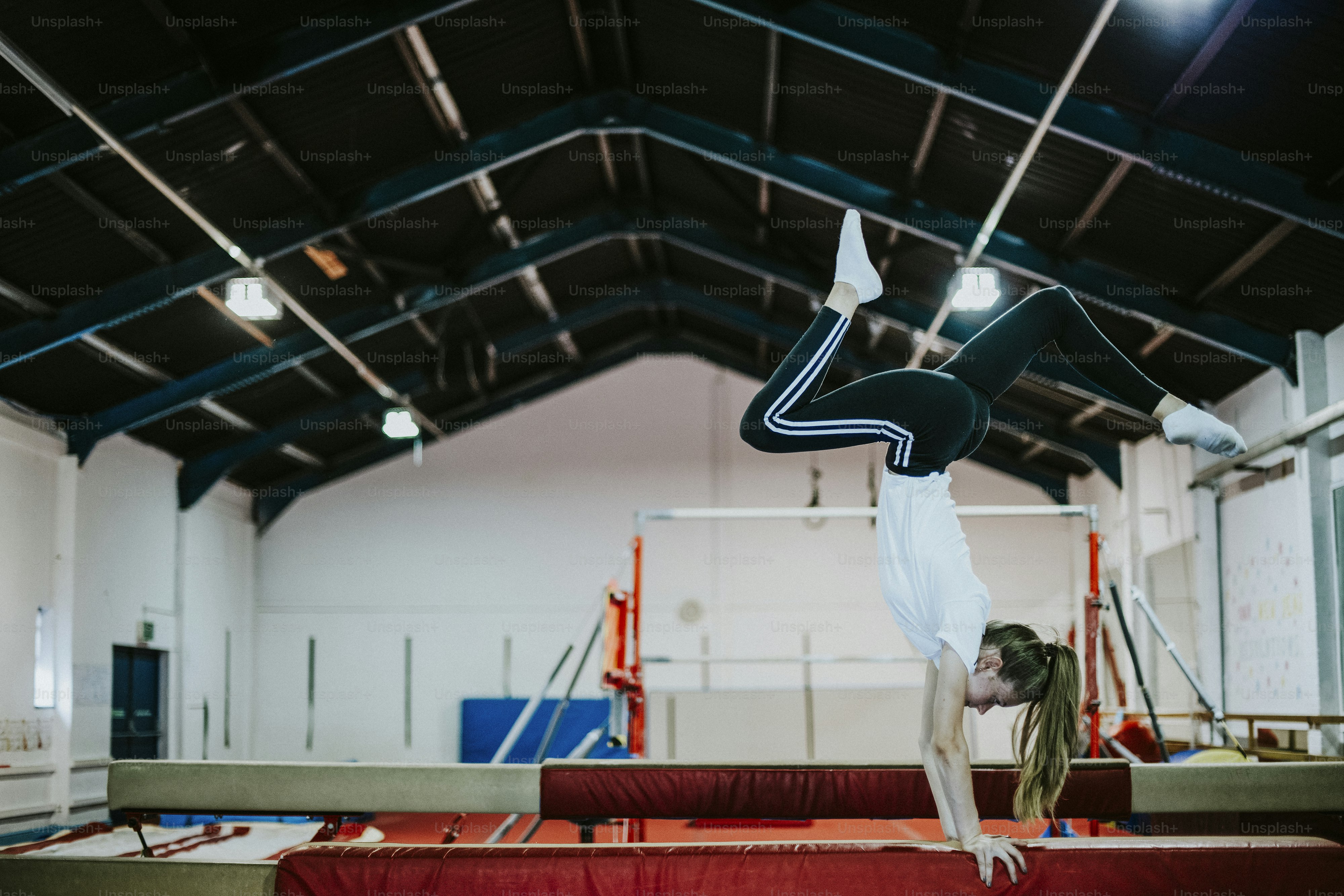Female gymnast doing a handstand on a balance beam photo – Athleticism ...