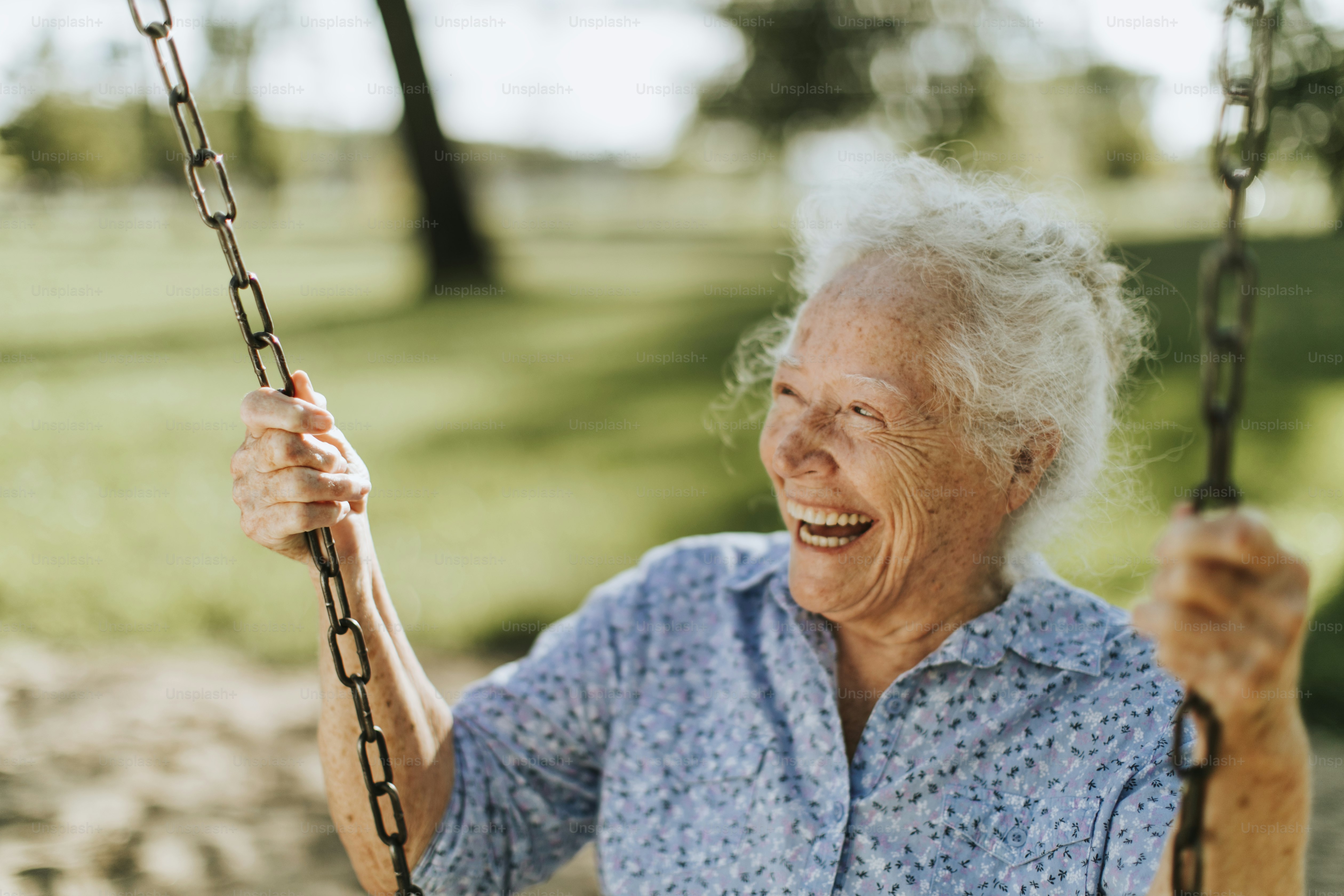 Cheerful senior woman on a swing at a playground photo – Happy Image on ...