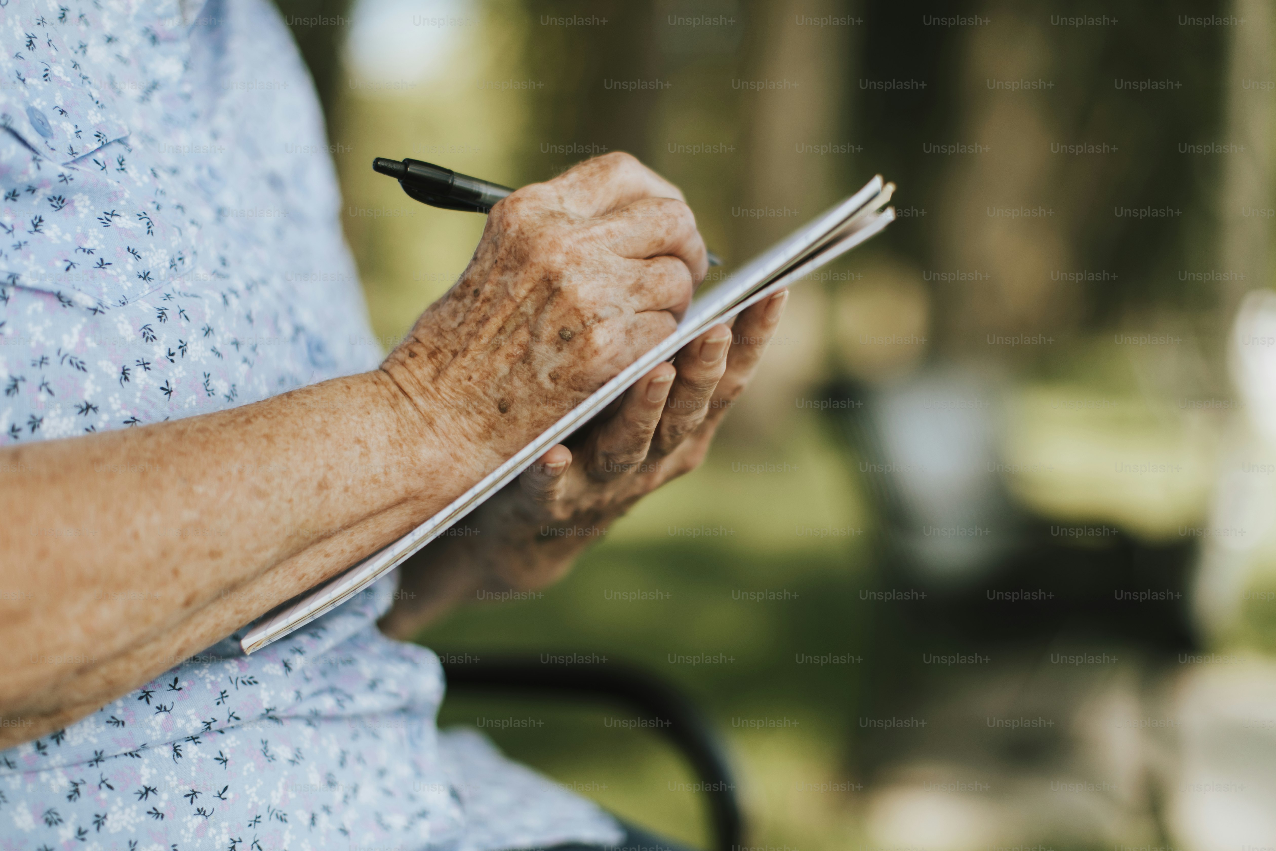 Senior woman writing down her memories into a notebook photo – Hand ...