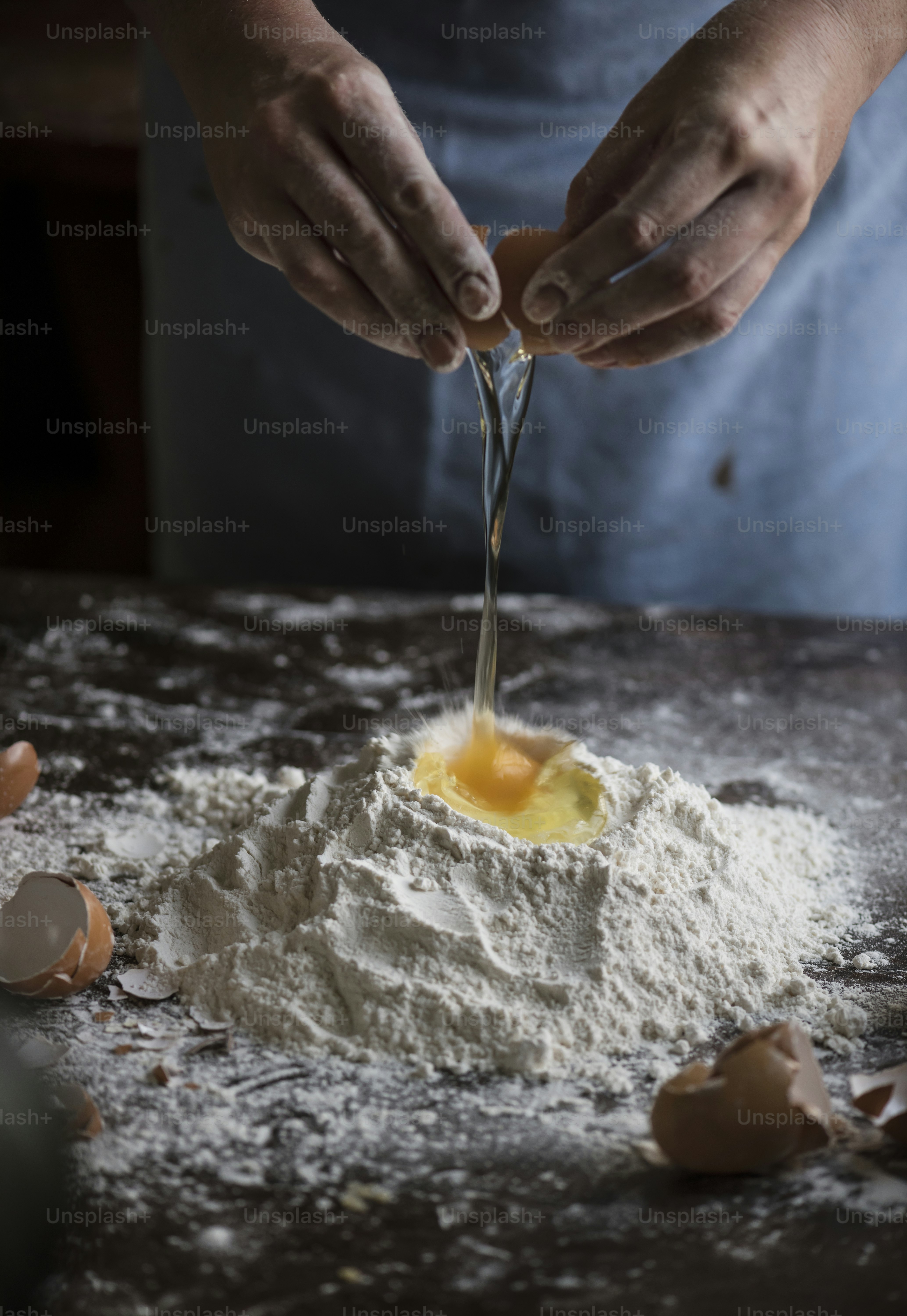 Baker breaking an egg into a flour mixture photo – Cereal plant Image ...