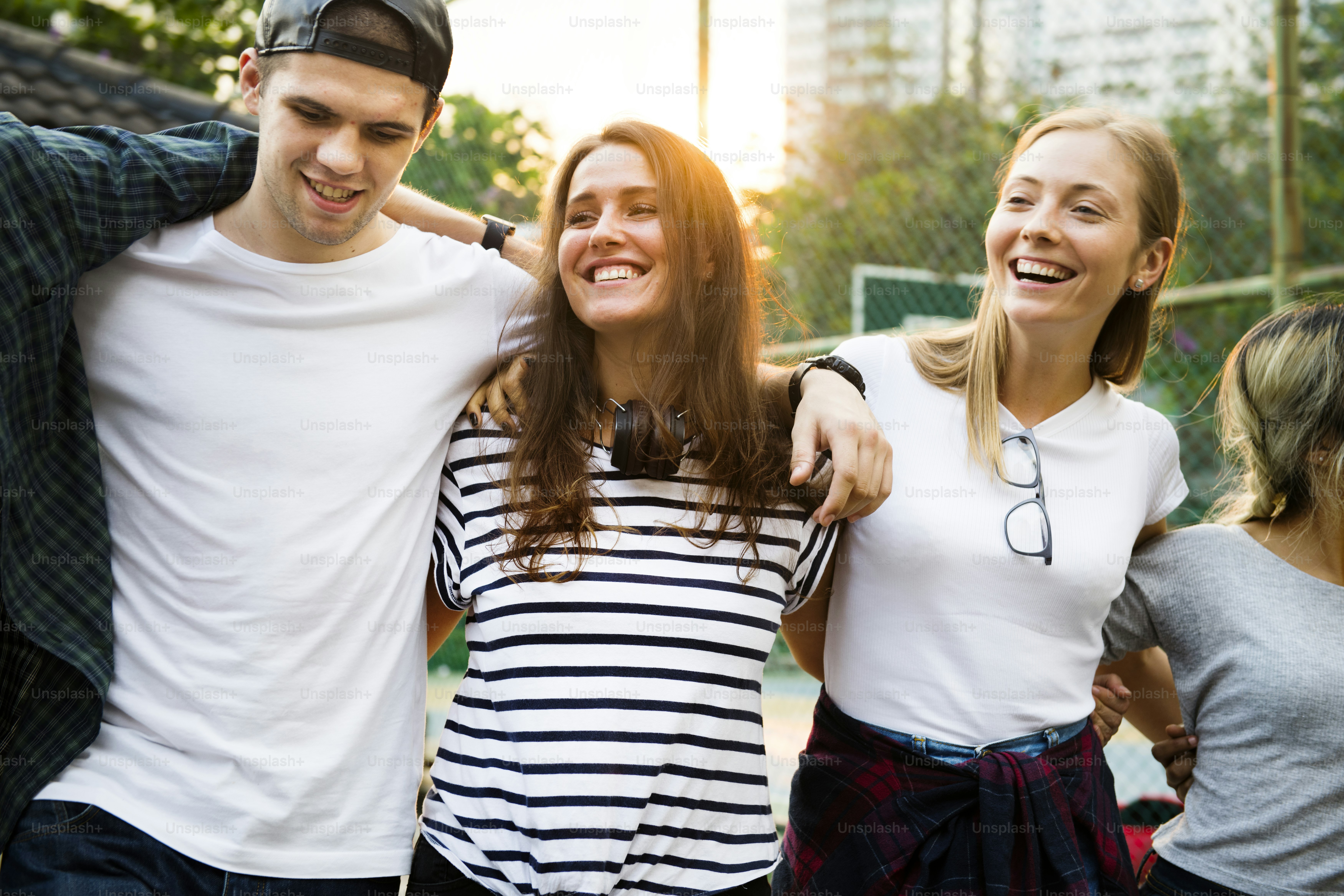 Smiling happy young adult friends arms around shoulder outdoors ...