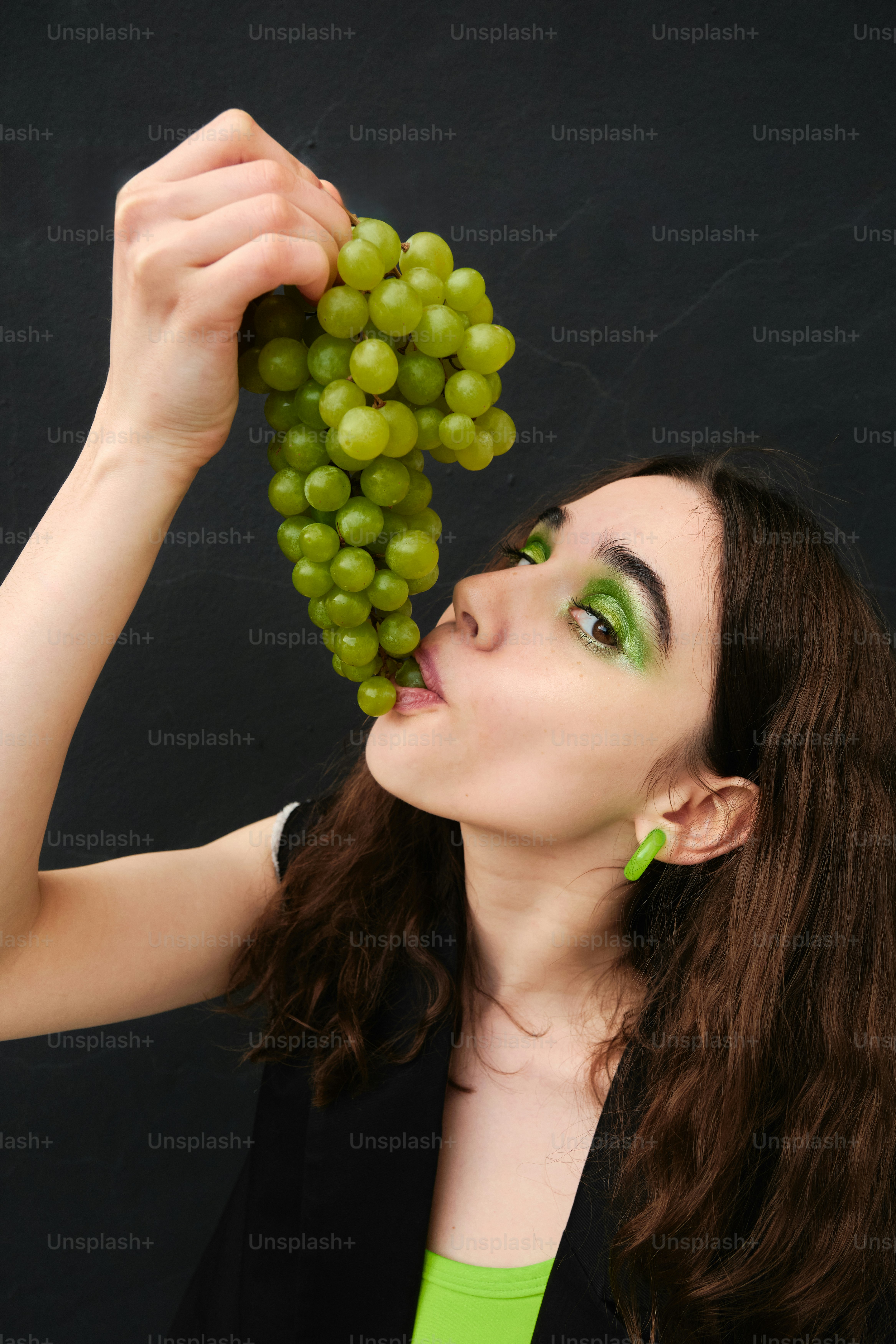 A woman holding a bunch of grapes up to her face photo – Generation z ...