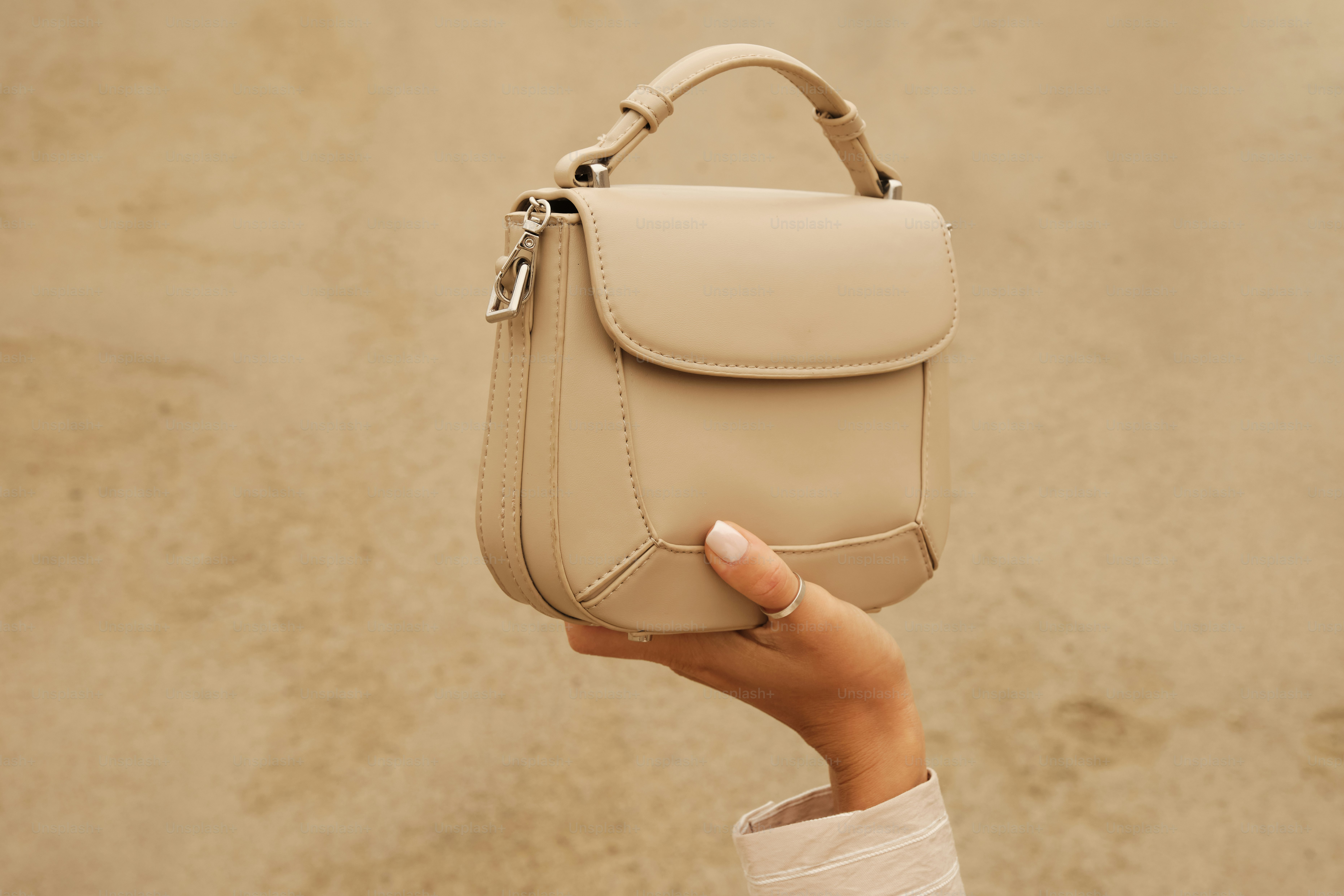 A woman holding a beige purse in her hand photo – Neutral aesthetic ...