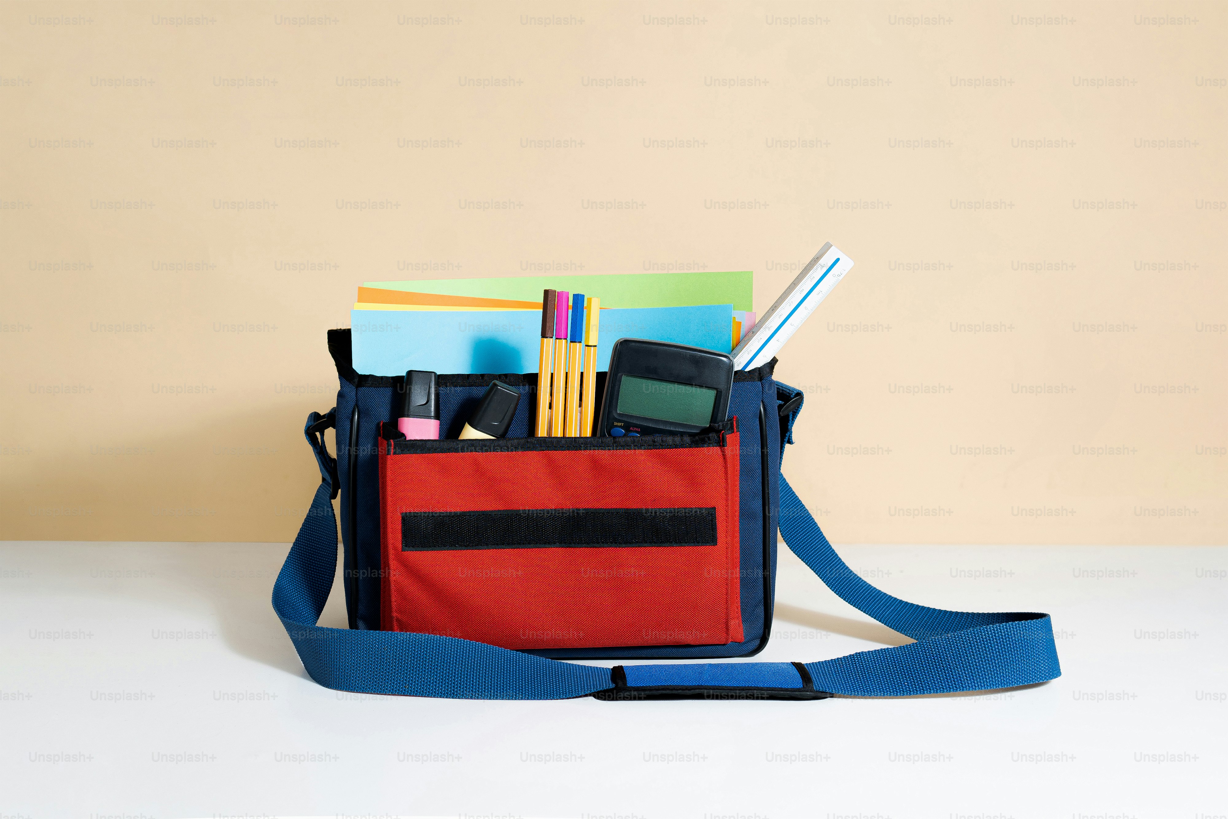A red and blue bag filled with school supplies photo – School symbols ...