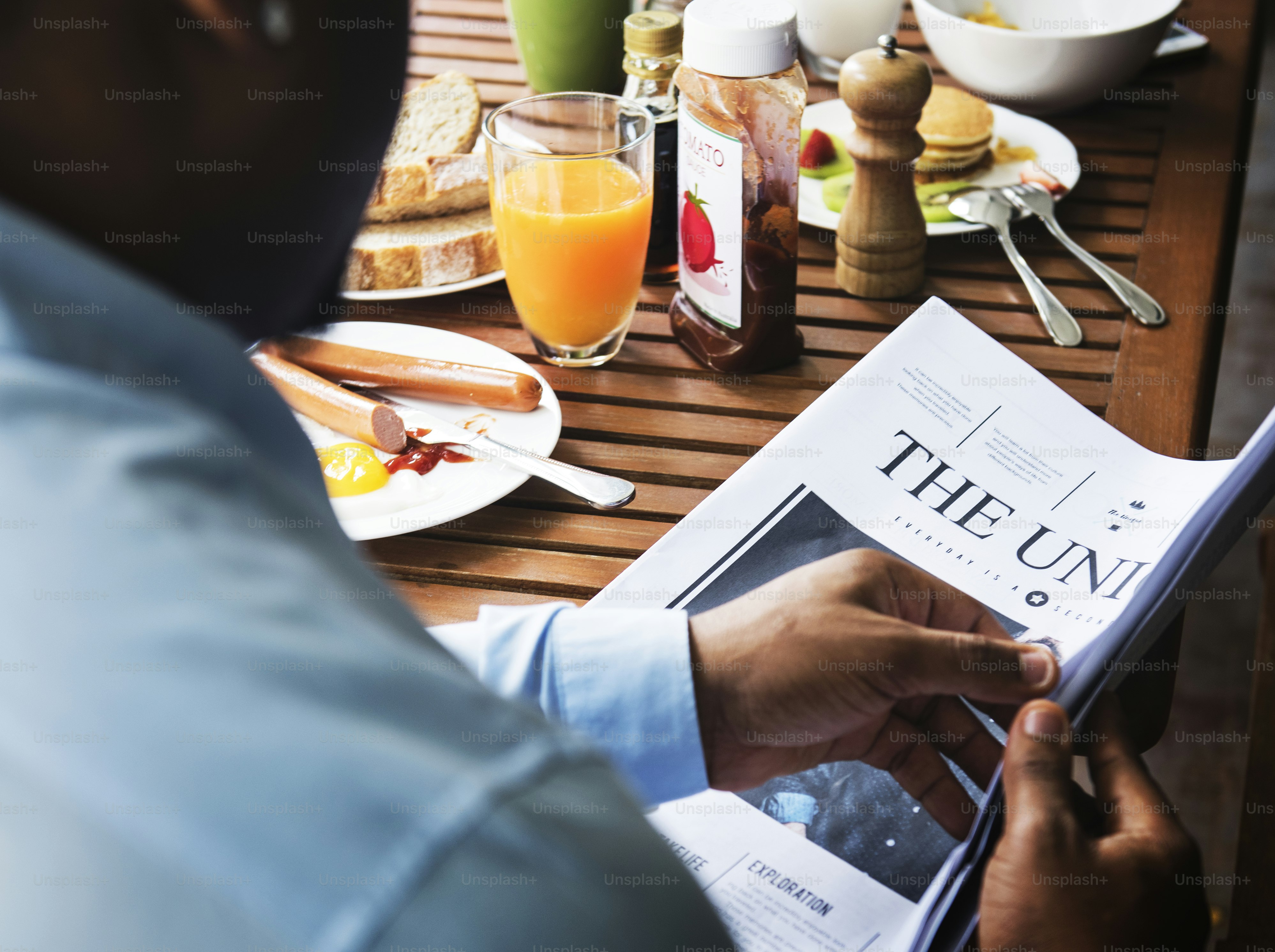Rear view of black man reading newspaper while having breakfast photo ...