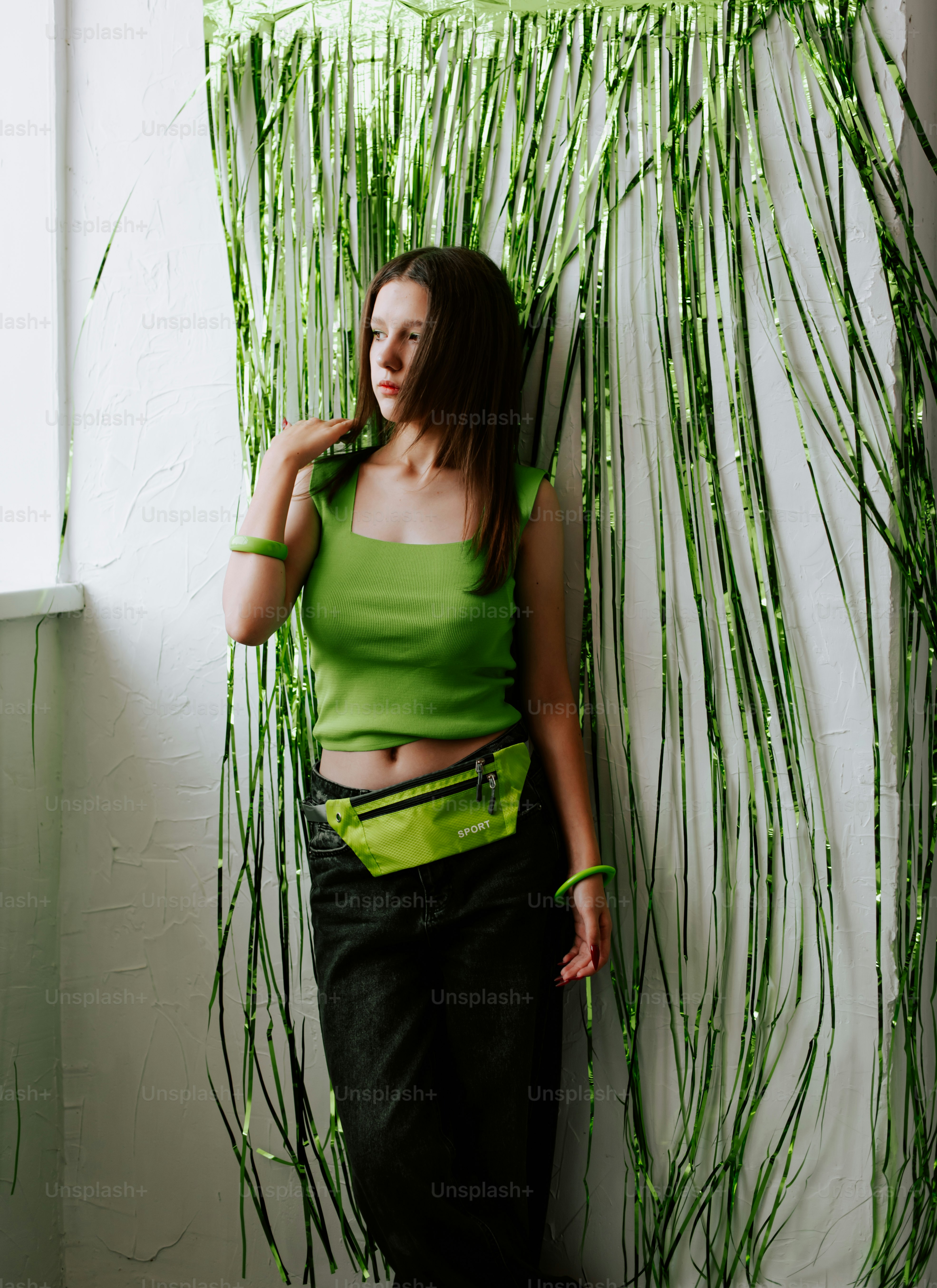 A woman leaning against a wall with green streamers photo – Bum bag ...