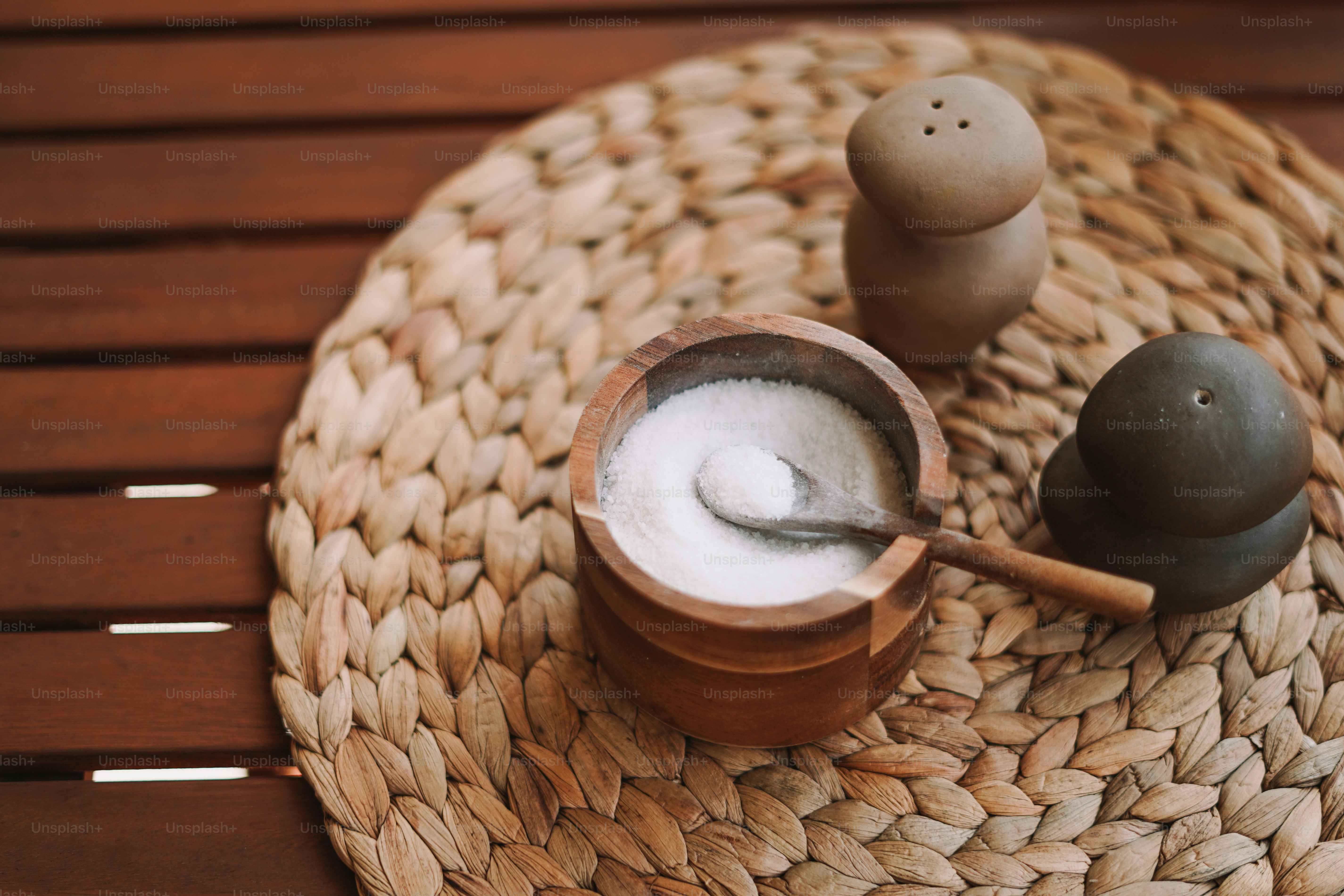 A wooden table topped with a bowl and two salt shakers photo – Salt and ...