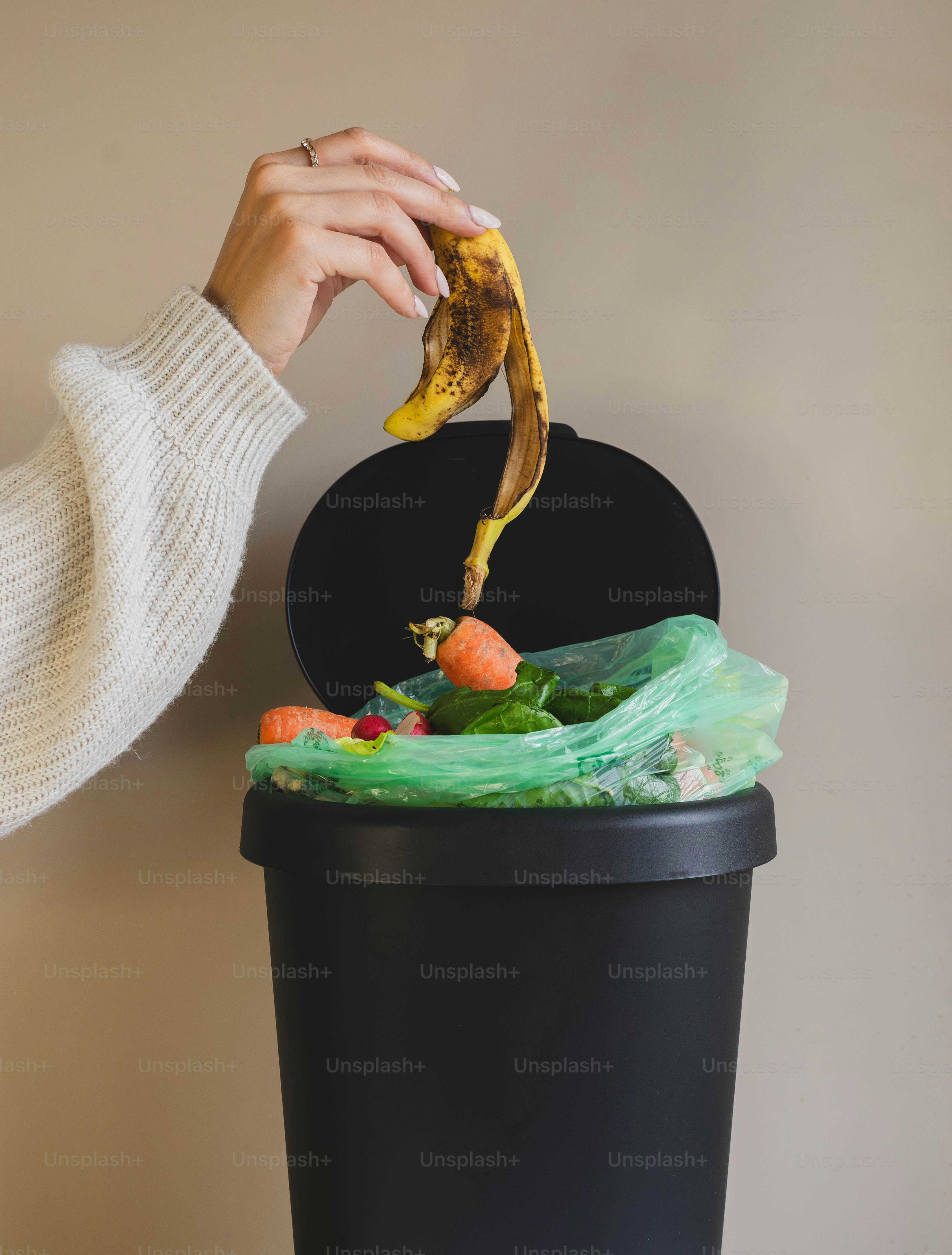 Eine Frau wirft eine Banane in einen Mülleimer Foto – Bild zum Thema ...