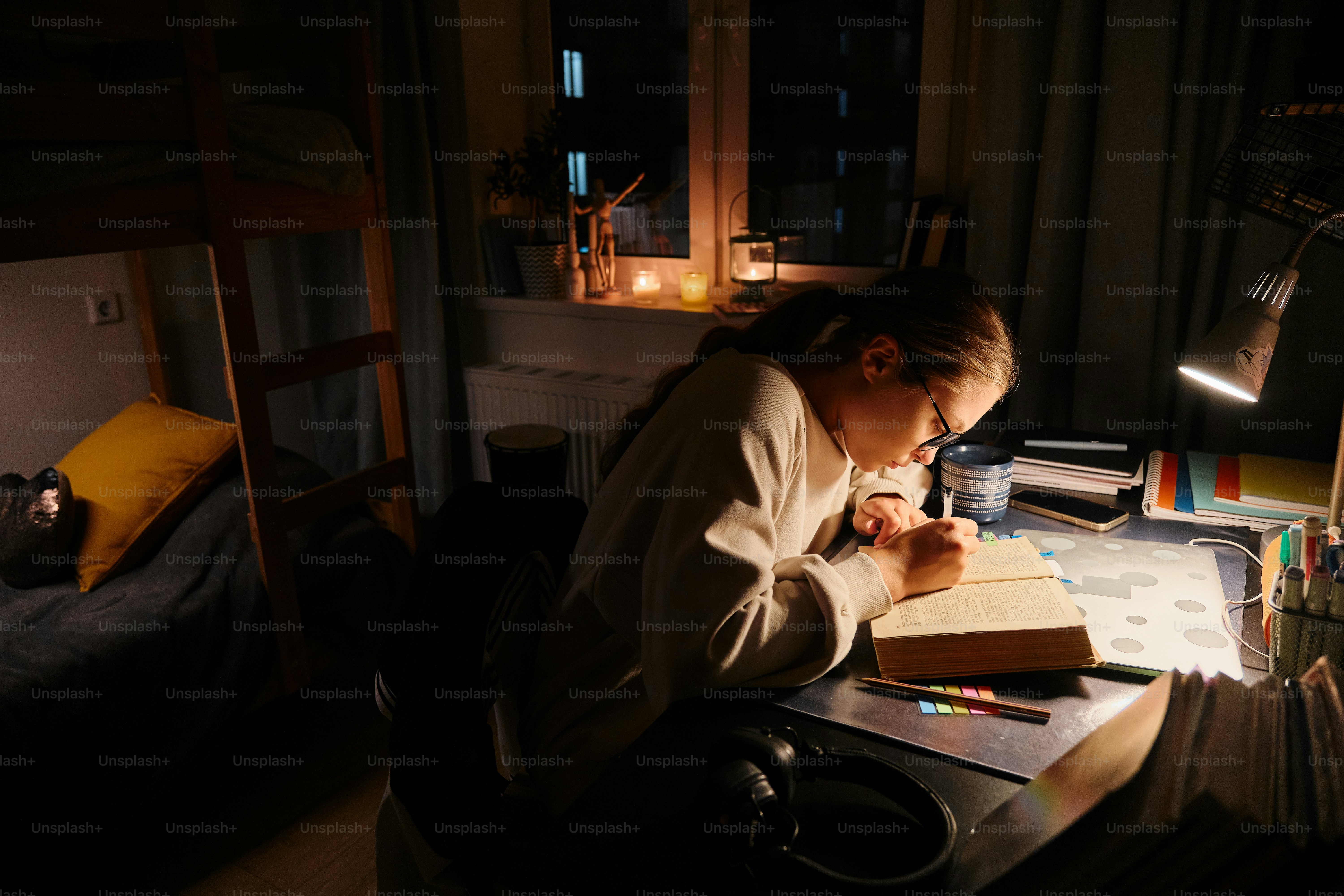 A person sitting at a desk writing in a book photo – Student Image on ...