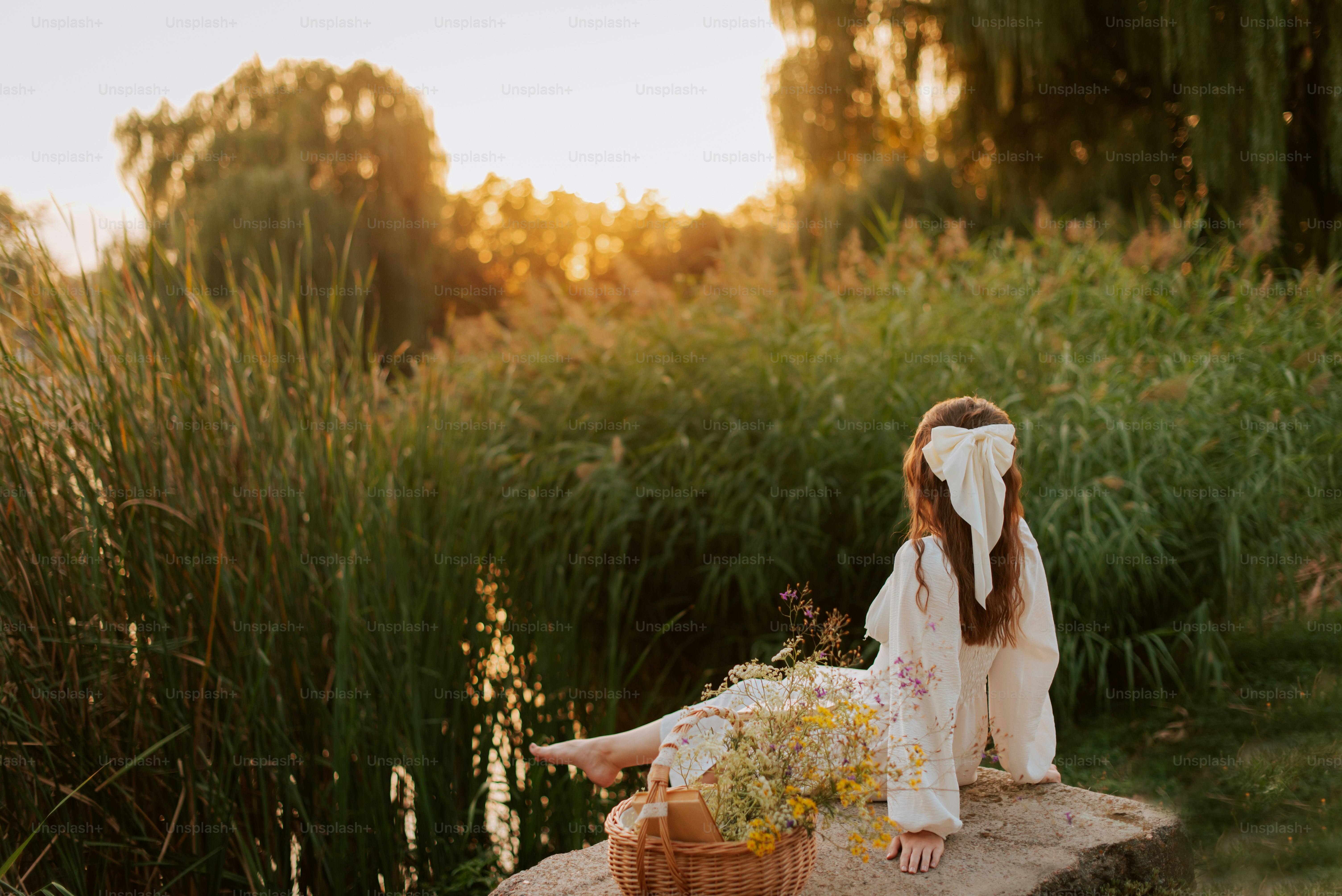 A woman in a white dress sitting on a rock photo – Cottagecore Image on ...