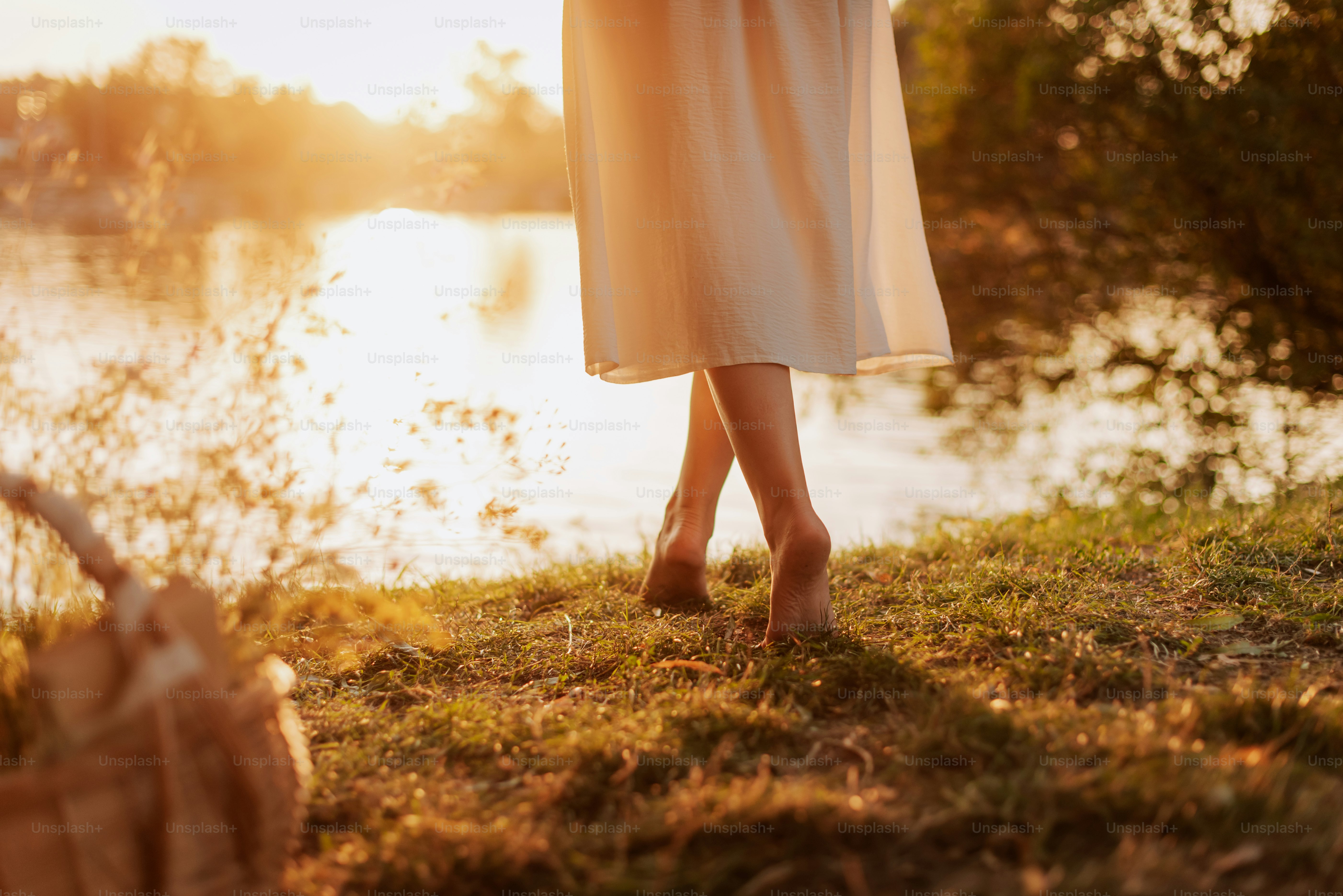A woman in a white dress standing by a lake photo – Demure Image on ...