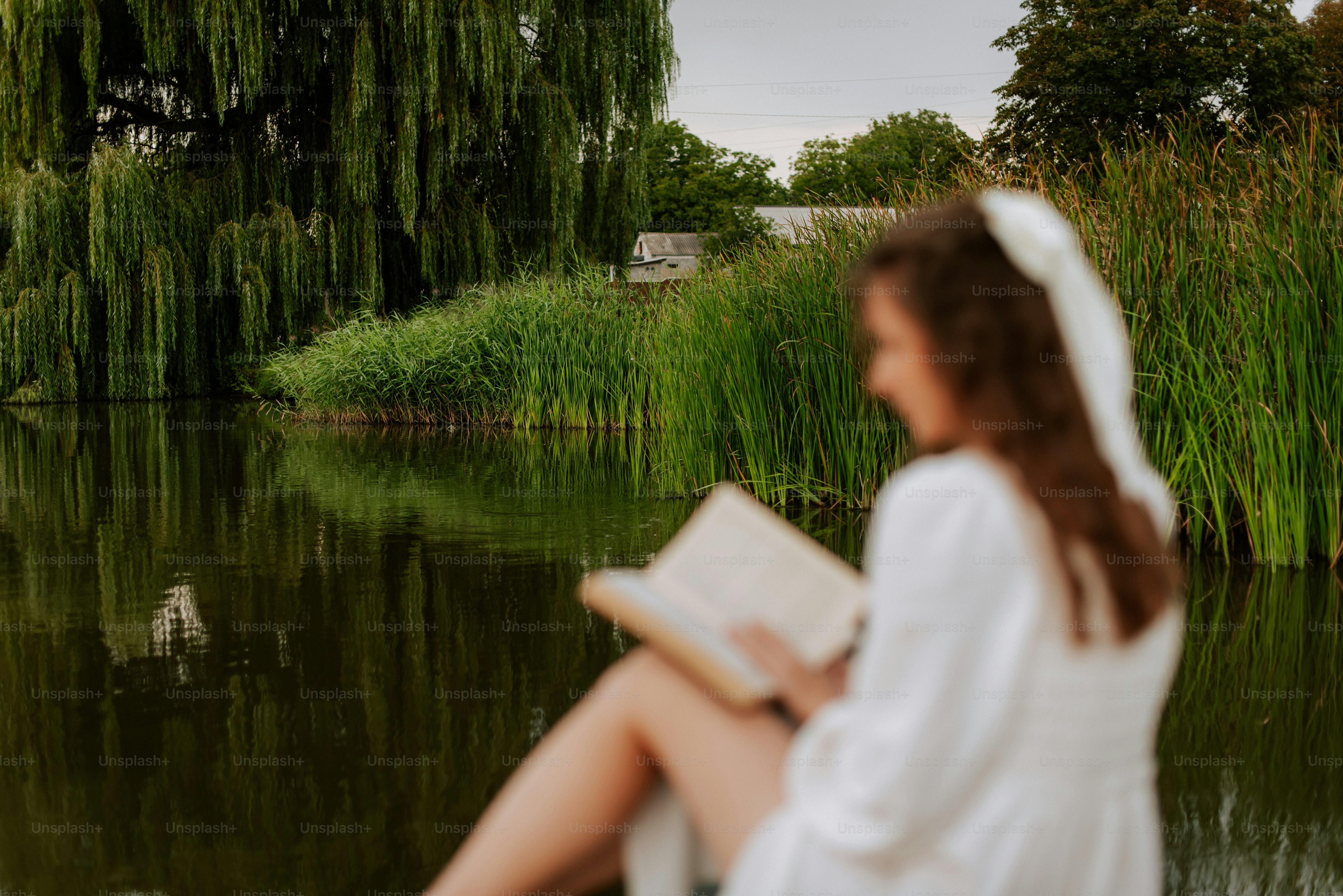 A woman sitting on a dock reading a book photo – Woman Image on Unsplash