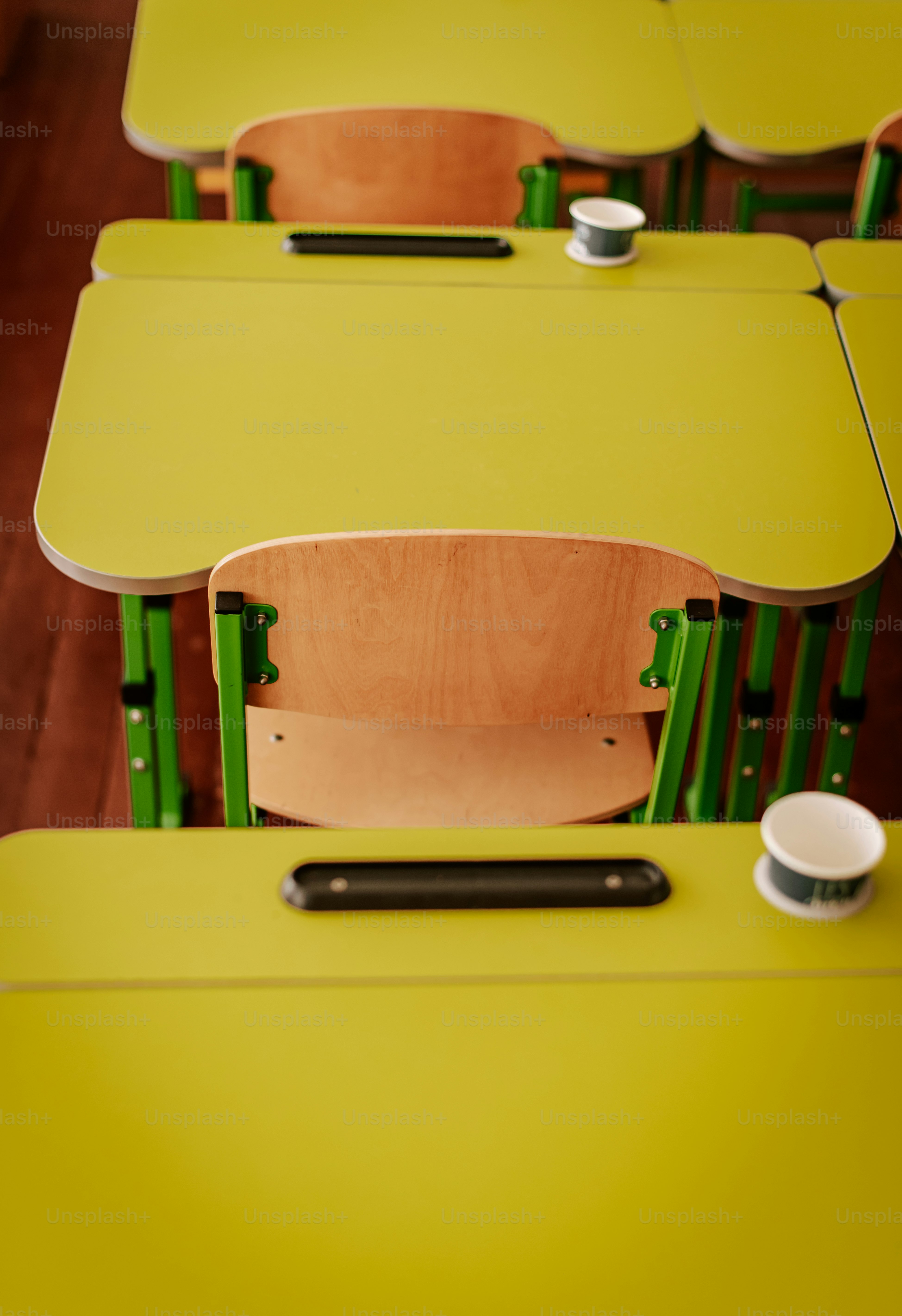 A row of yellow desks with green chairs photo – School symbols Image on ...