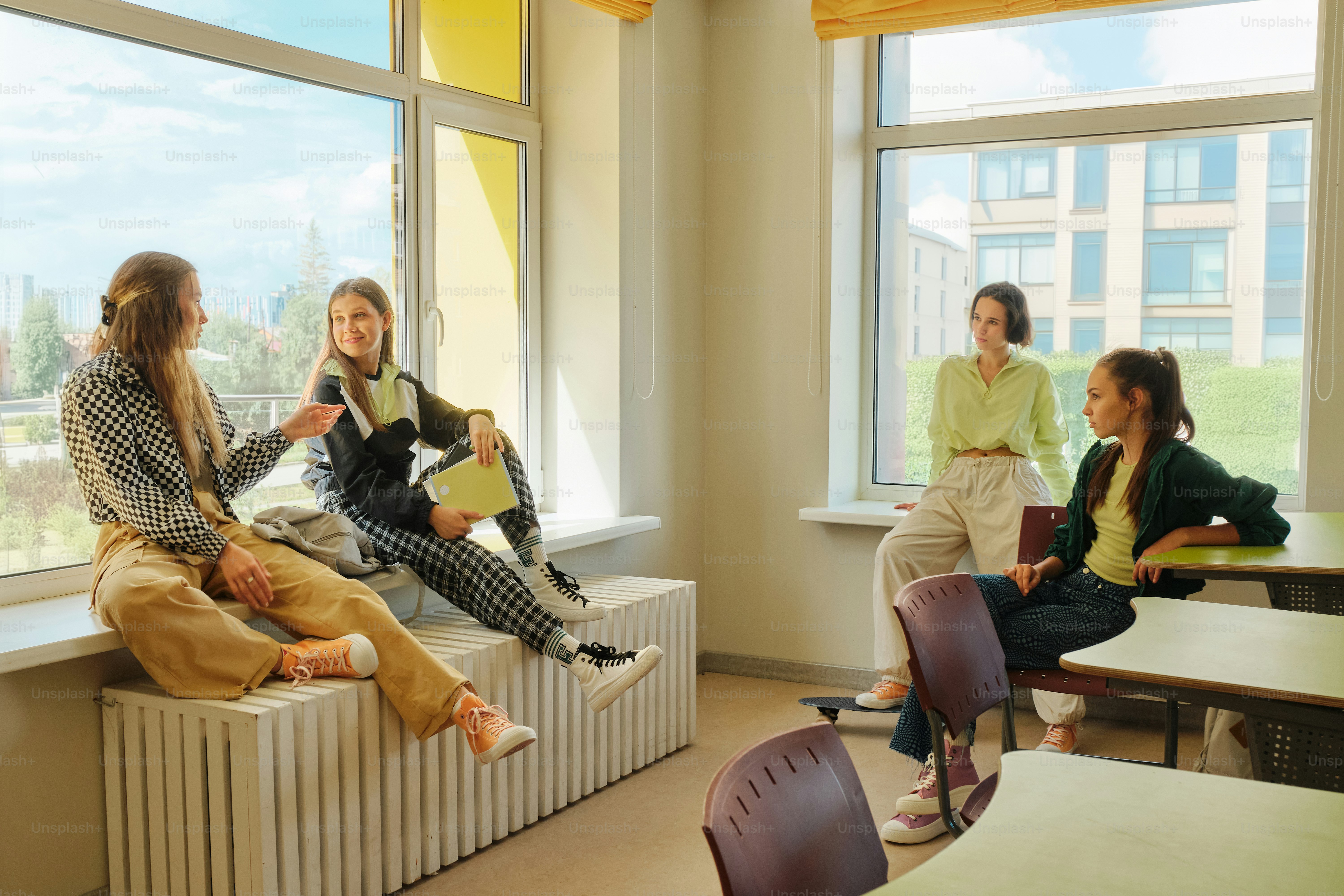 A group of girls sitting on a window sill photo – Classroom fashion ...