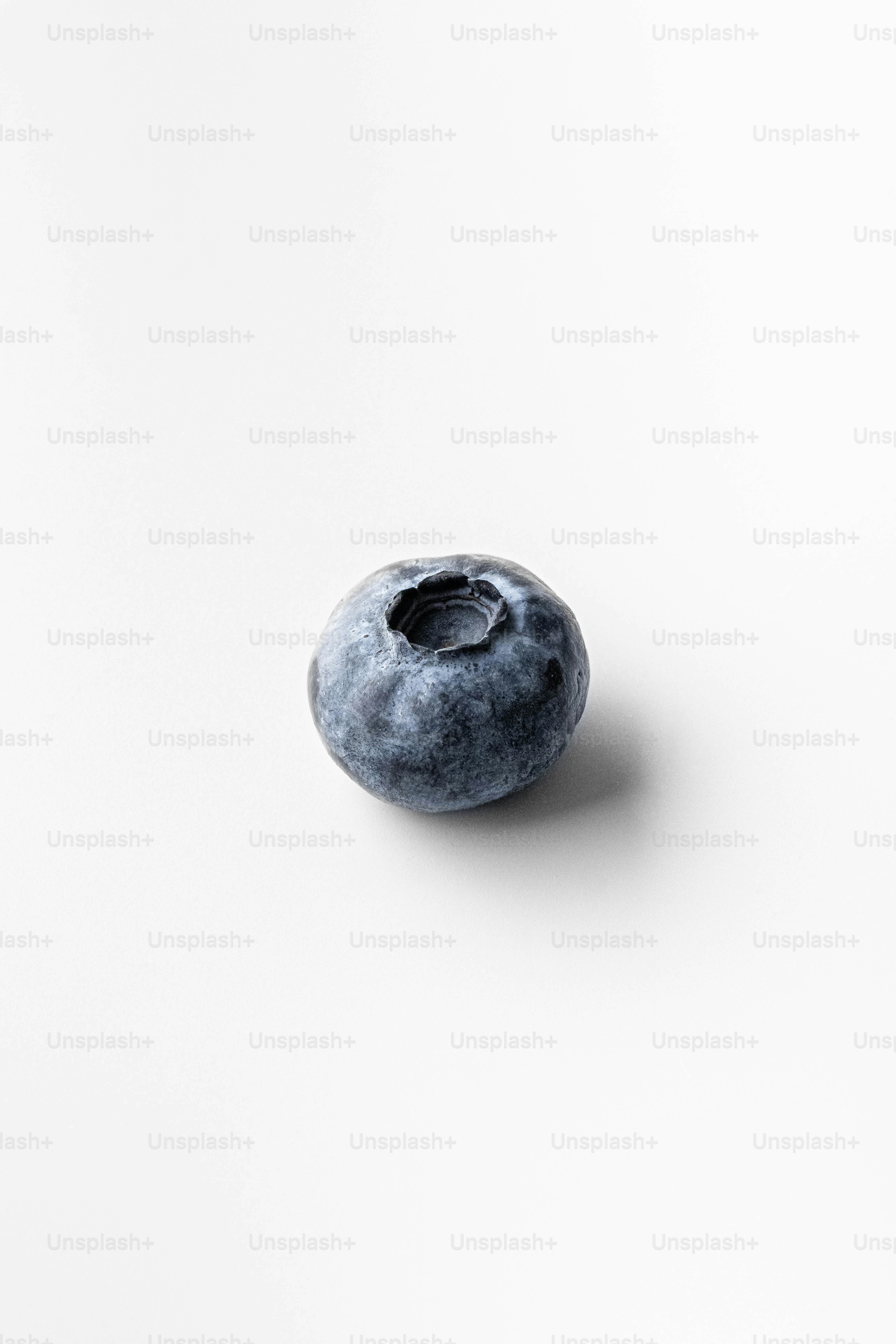 A single blueberry sitting on a white surface photo – Blueberry Image ...