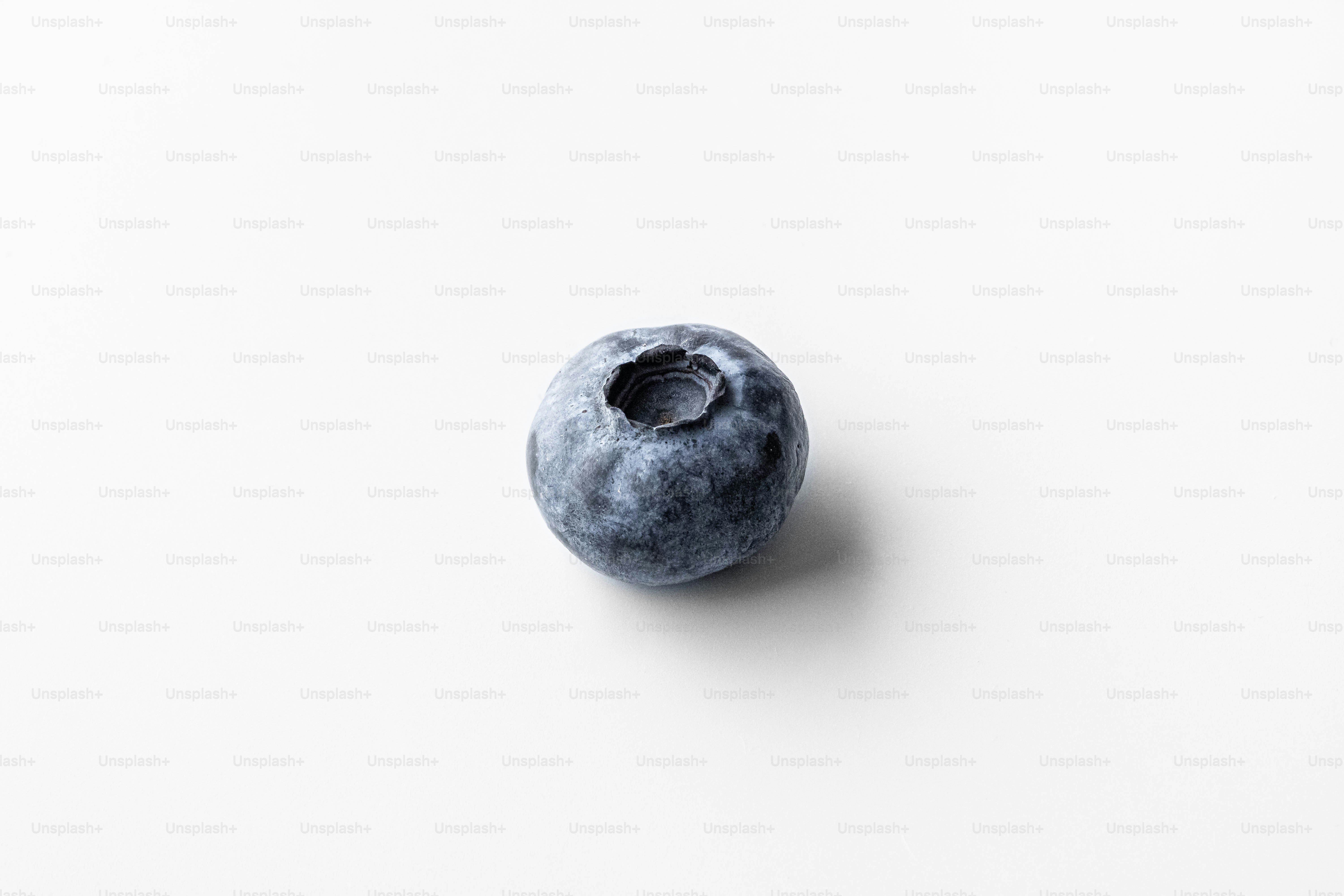 A single blueberry sitting on a white surface photo – Blueberries Image ...