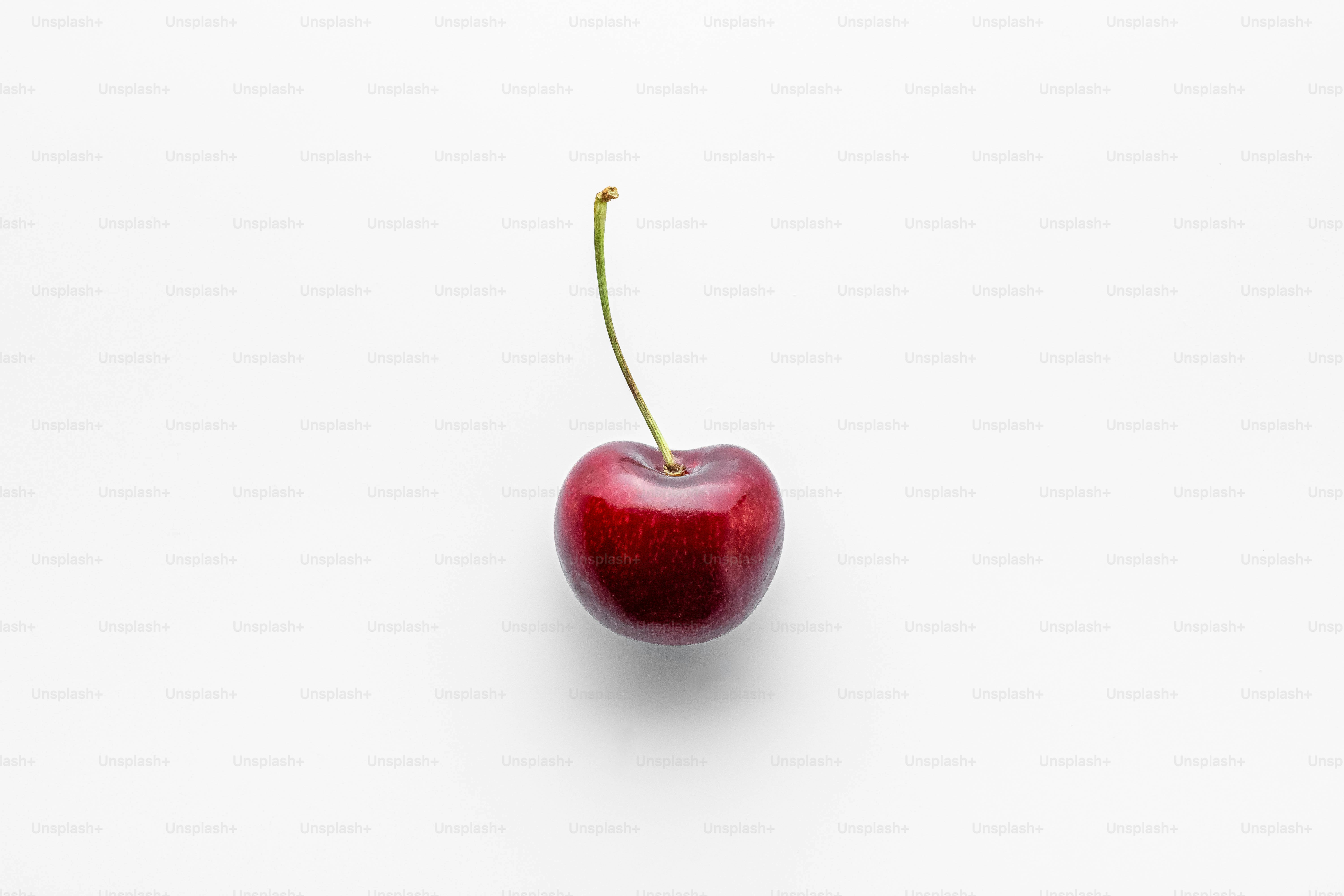 A single cherry sitting on top of a white surface photo – Cherry Image ...
