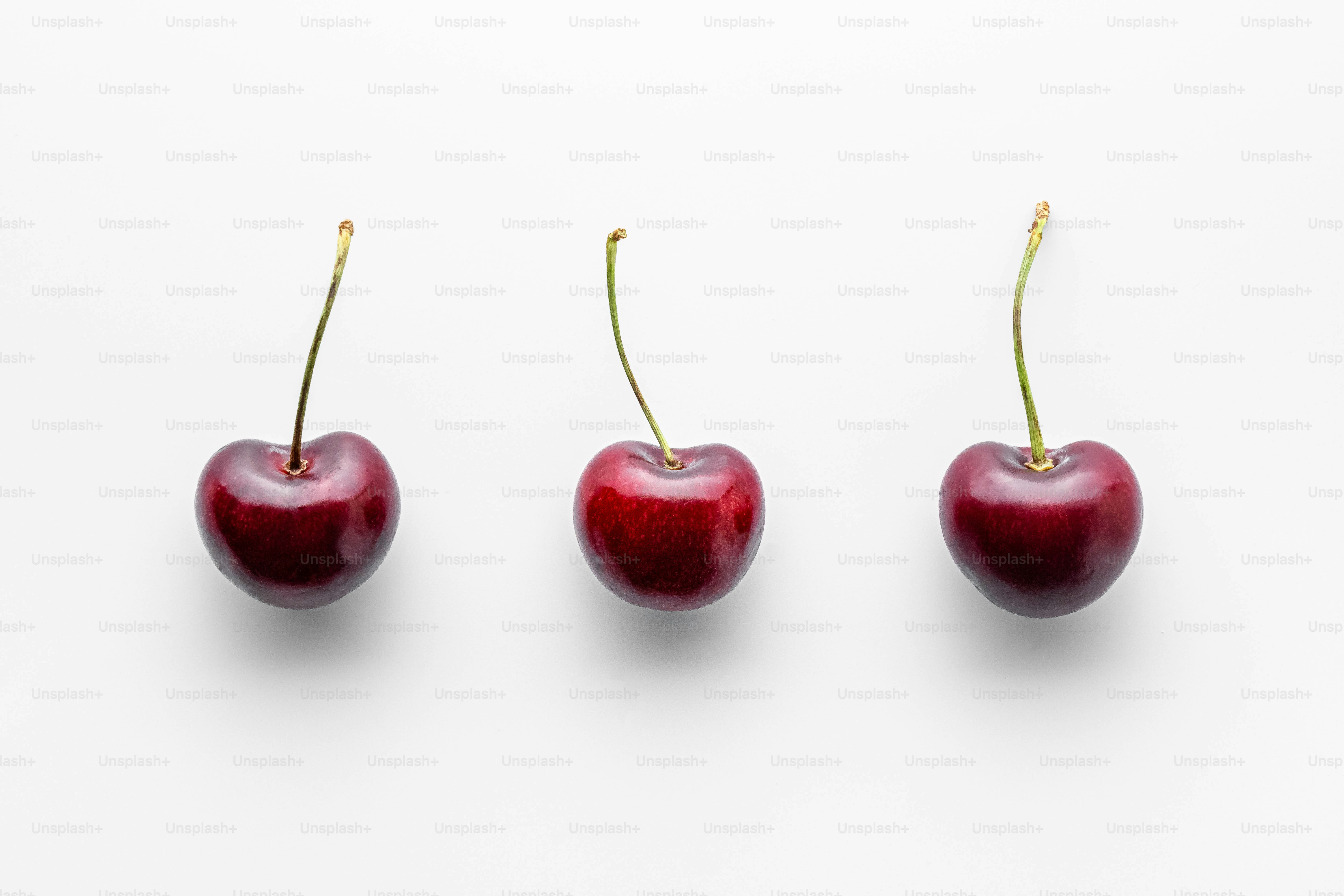 Three cherries in a row on a white surface photo – Cherries Image on ...