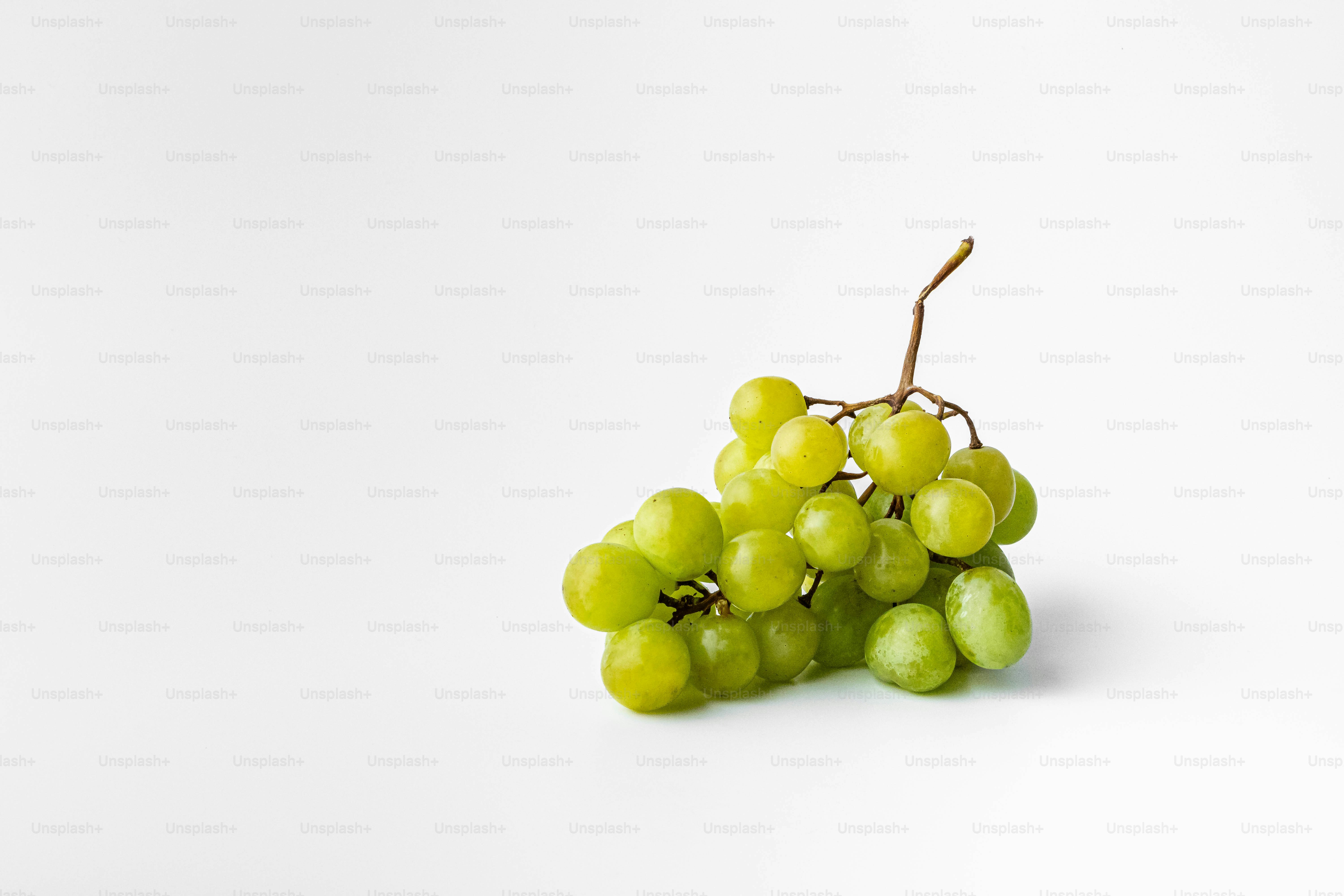 A bunch of green grapes sitting on top of a white table photo – Grapes ...