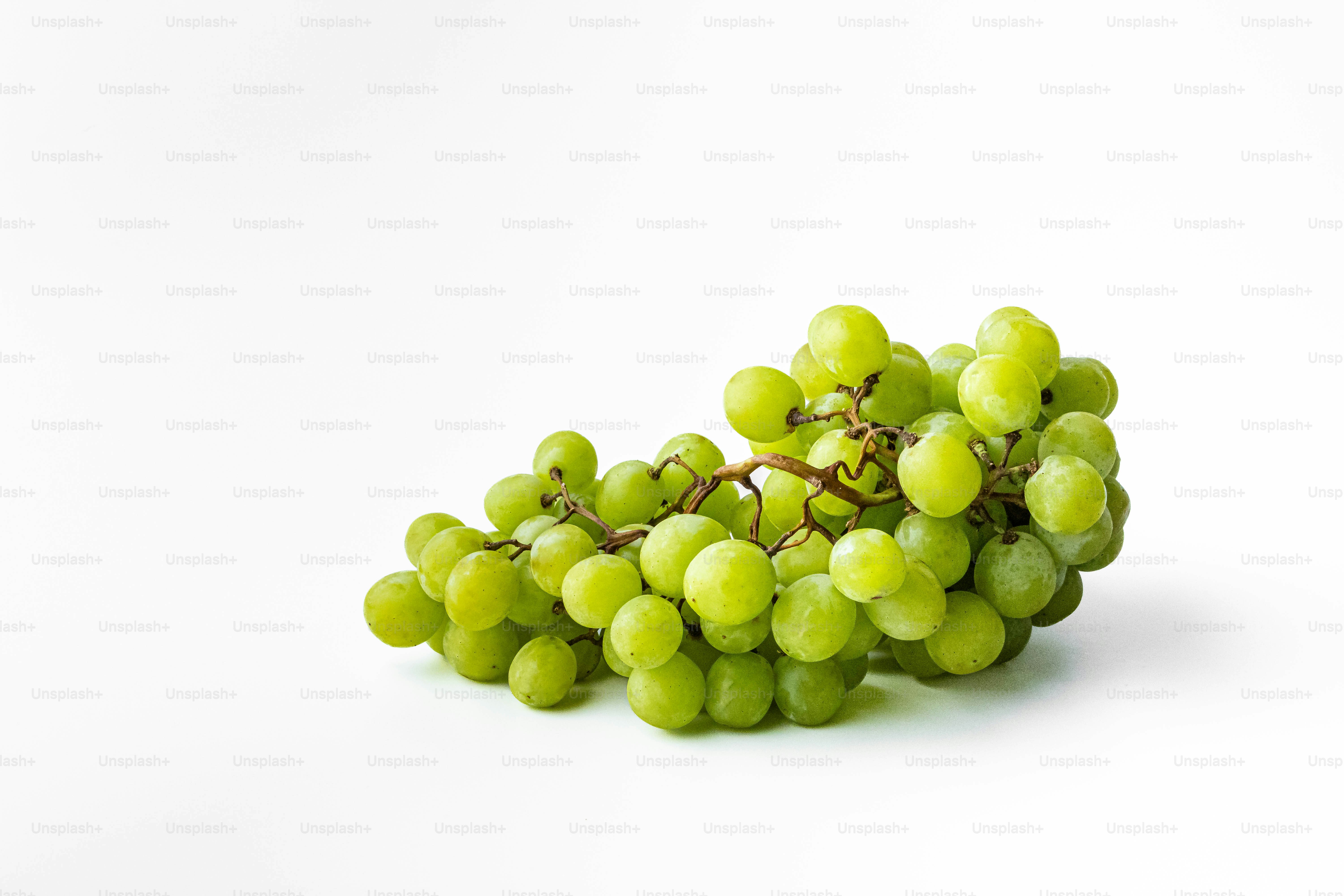 A bunch of green grapes hanging on a white wall photo – Grapes Image on ...