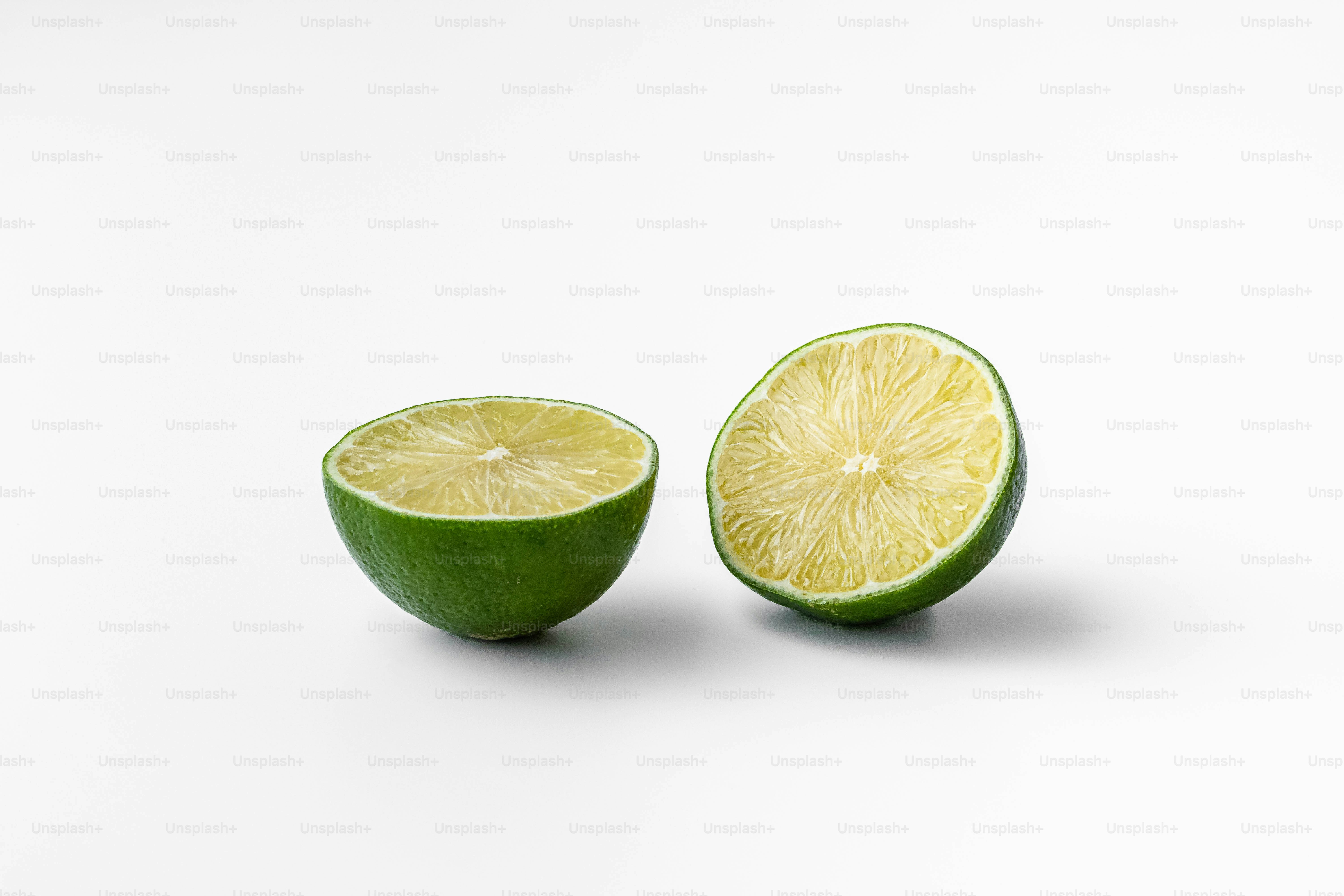 Two limes cut in half on a white surface photo – Food and drink Image ...