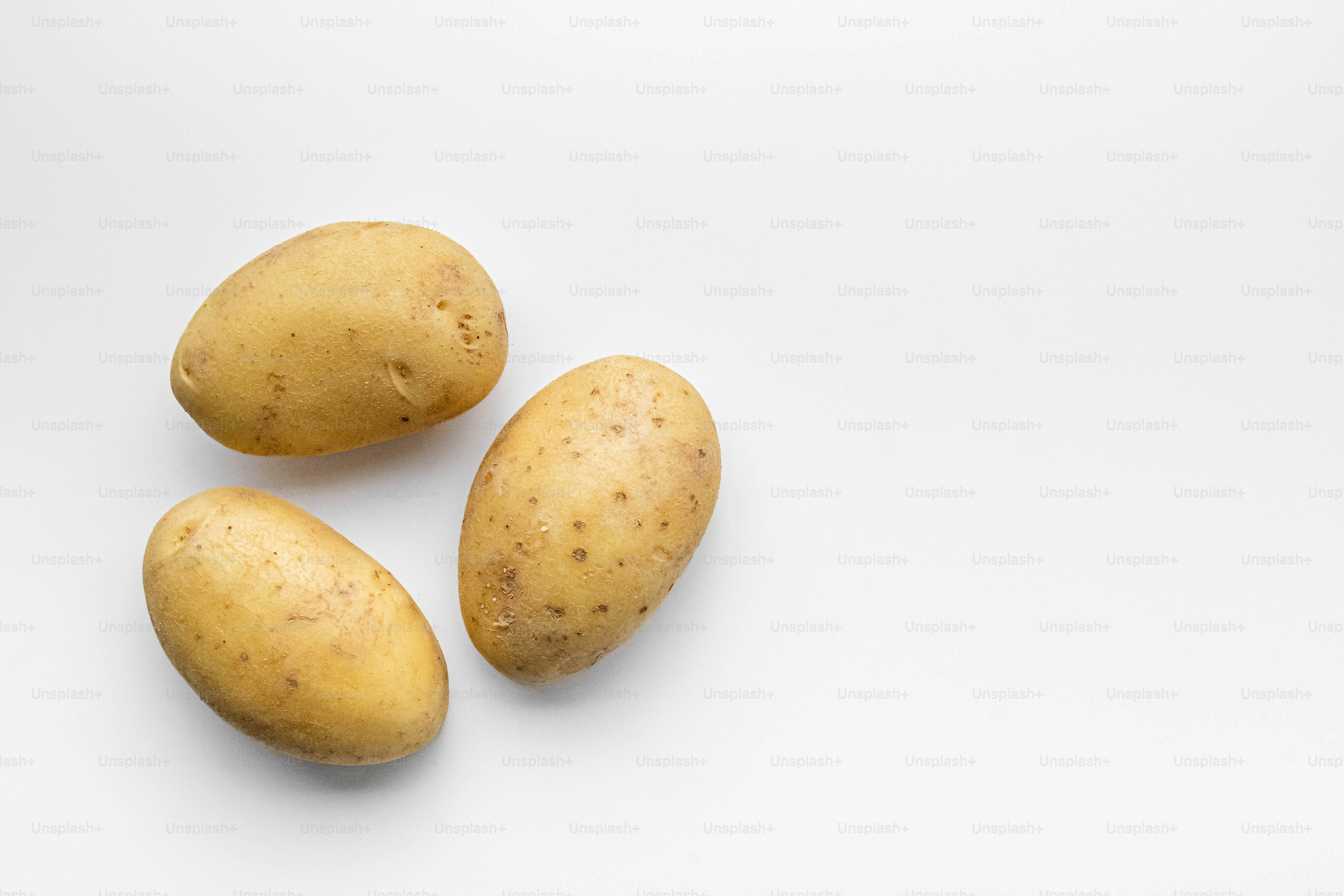 Three potatoes sitting next to each other on a white surface photo ...