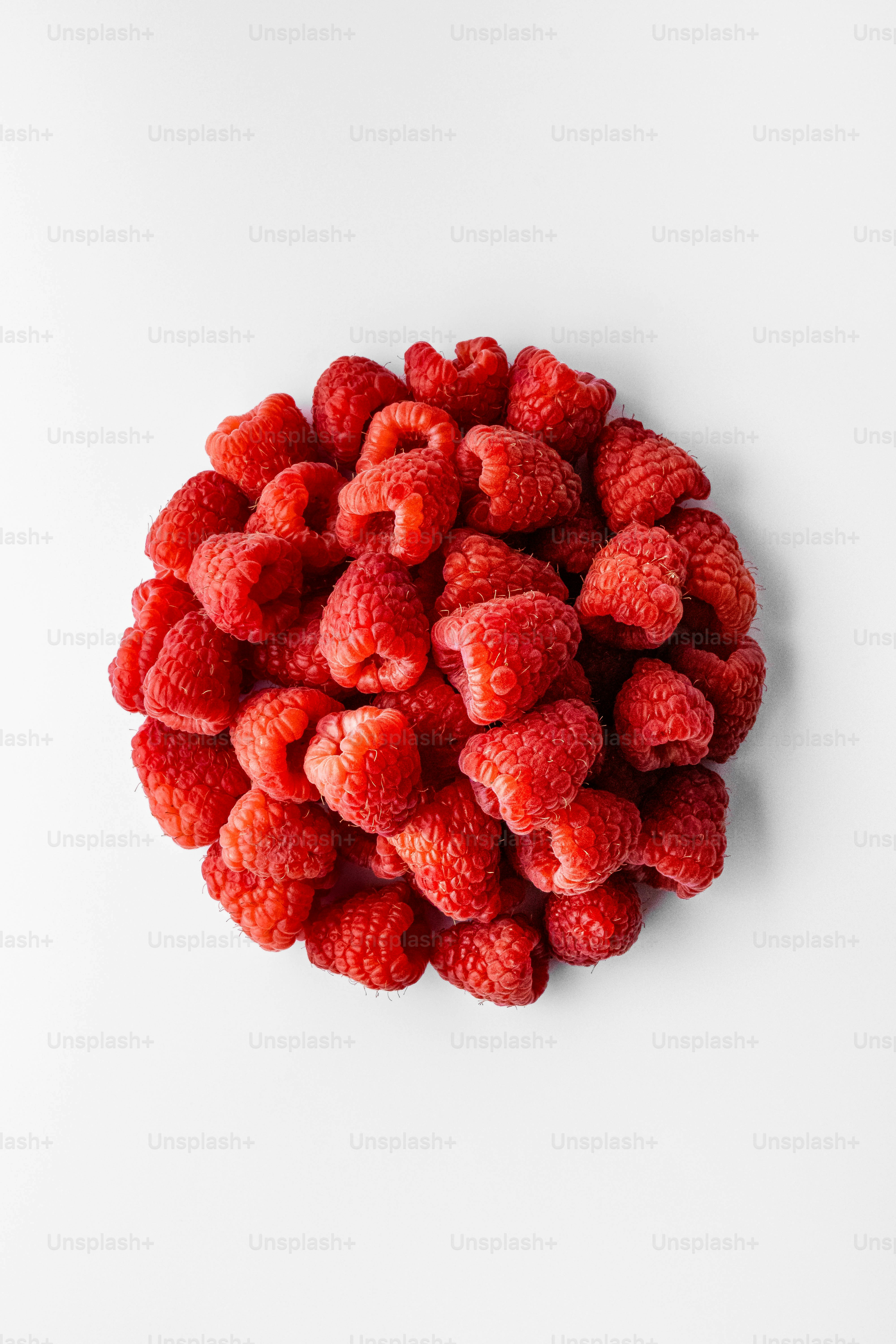 A pile of raspberries on a white surface photo – Raspberries Image on ...