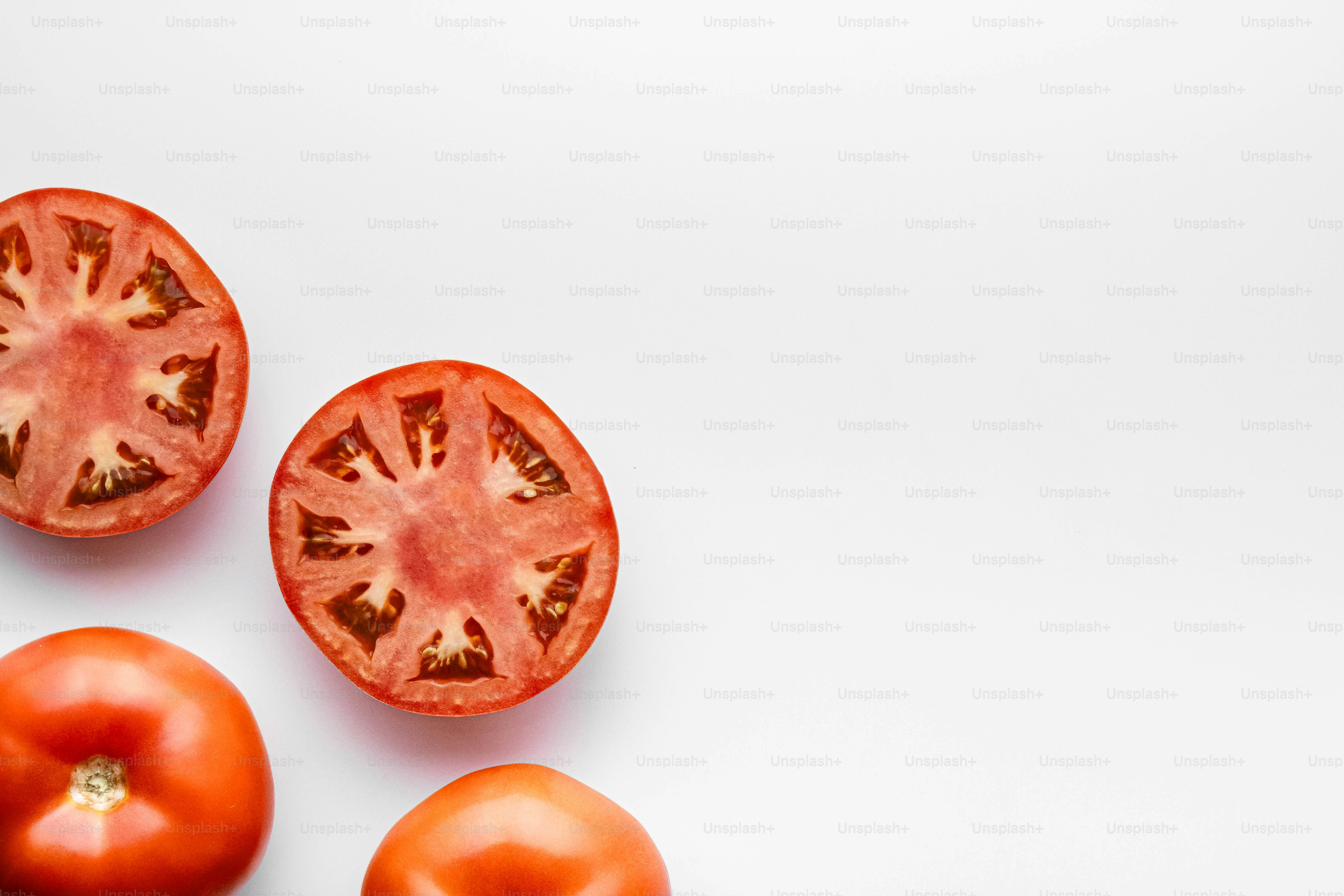 Un tomate cortado por la mitad sobre una superficie blanca foto ...