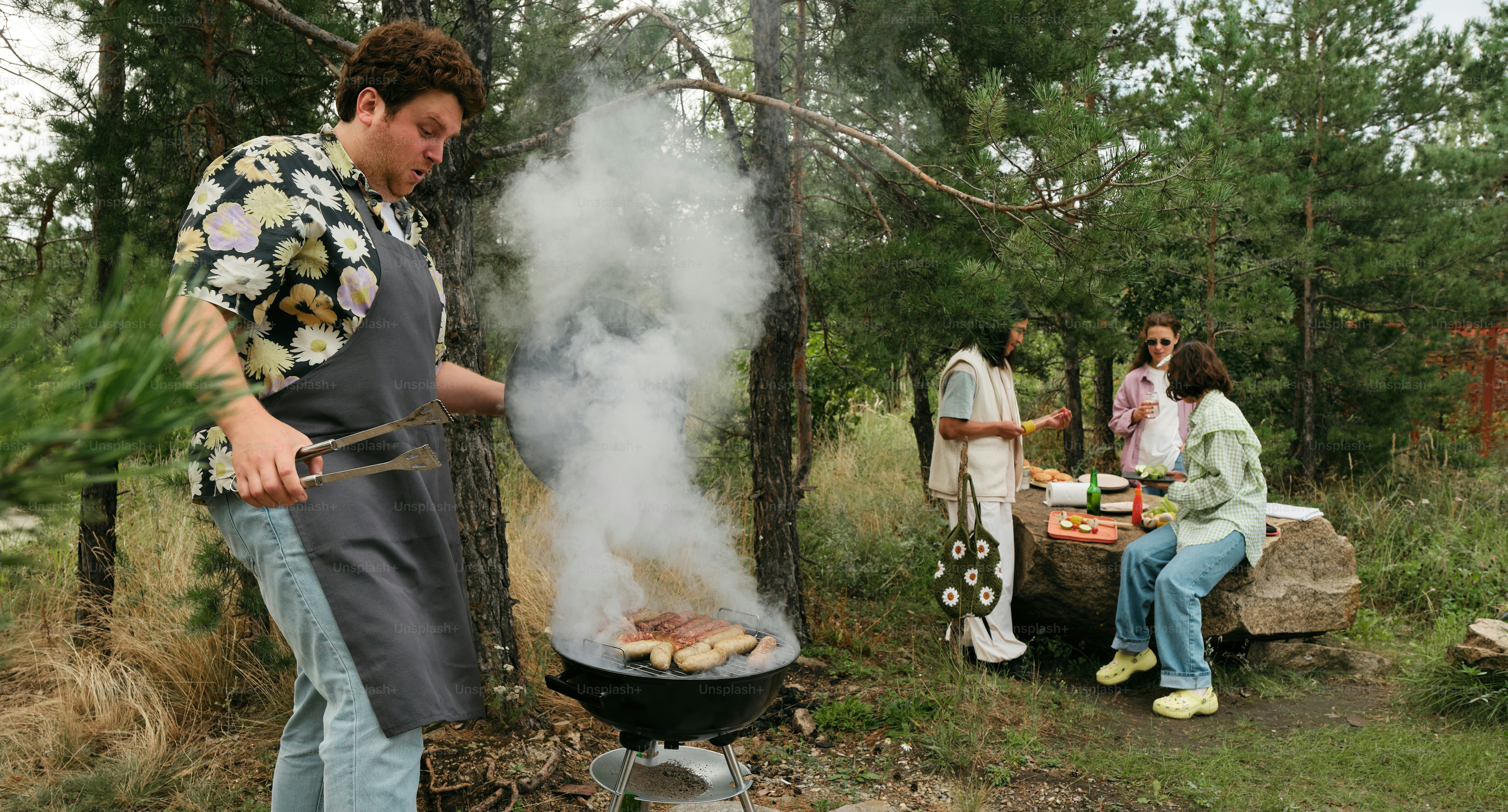 A group of people standing around a bbq grill photo – Grill Image on ...