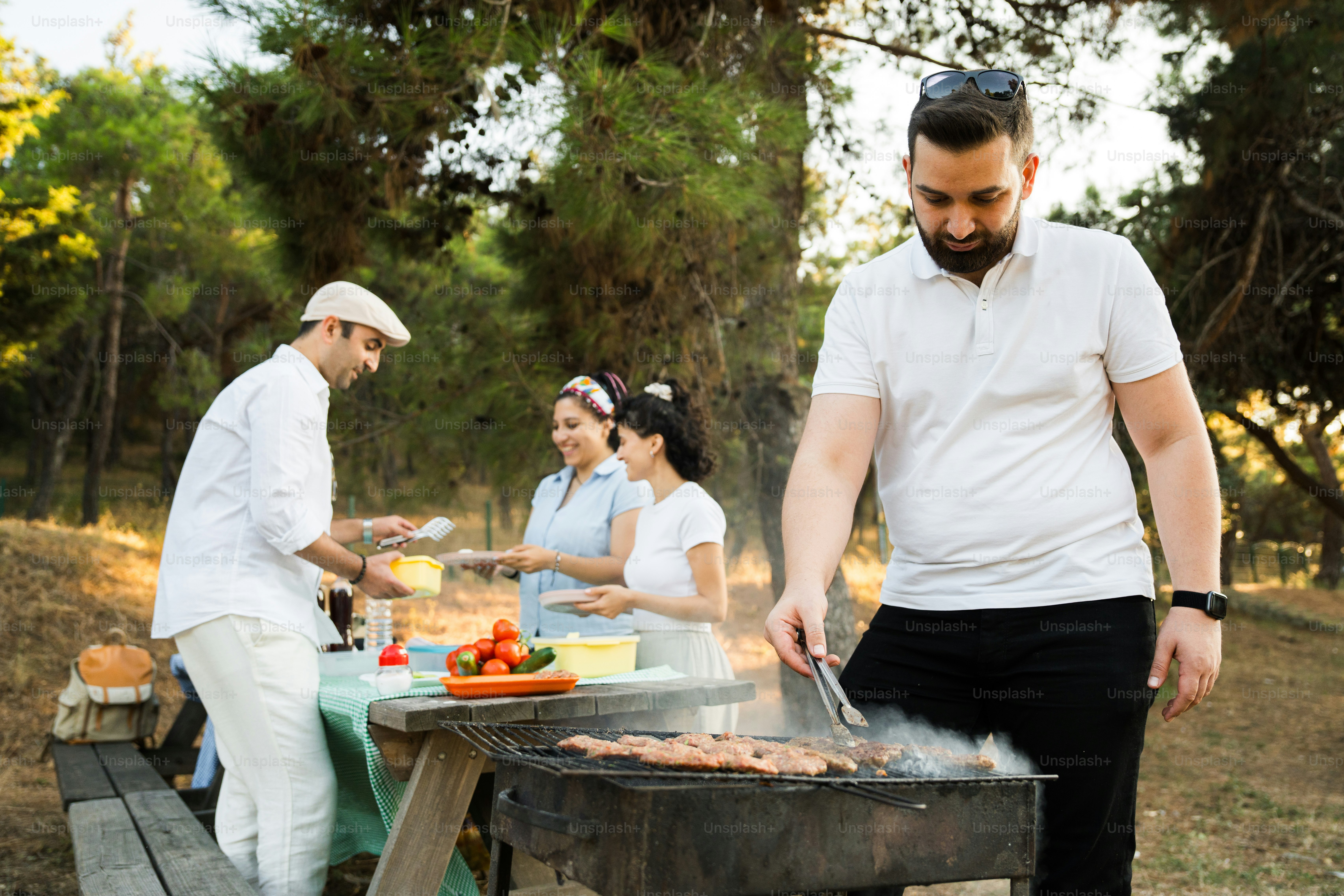 A group of people standing around a bbq grill photo – Barbecue Image on ...