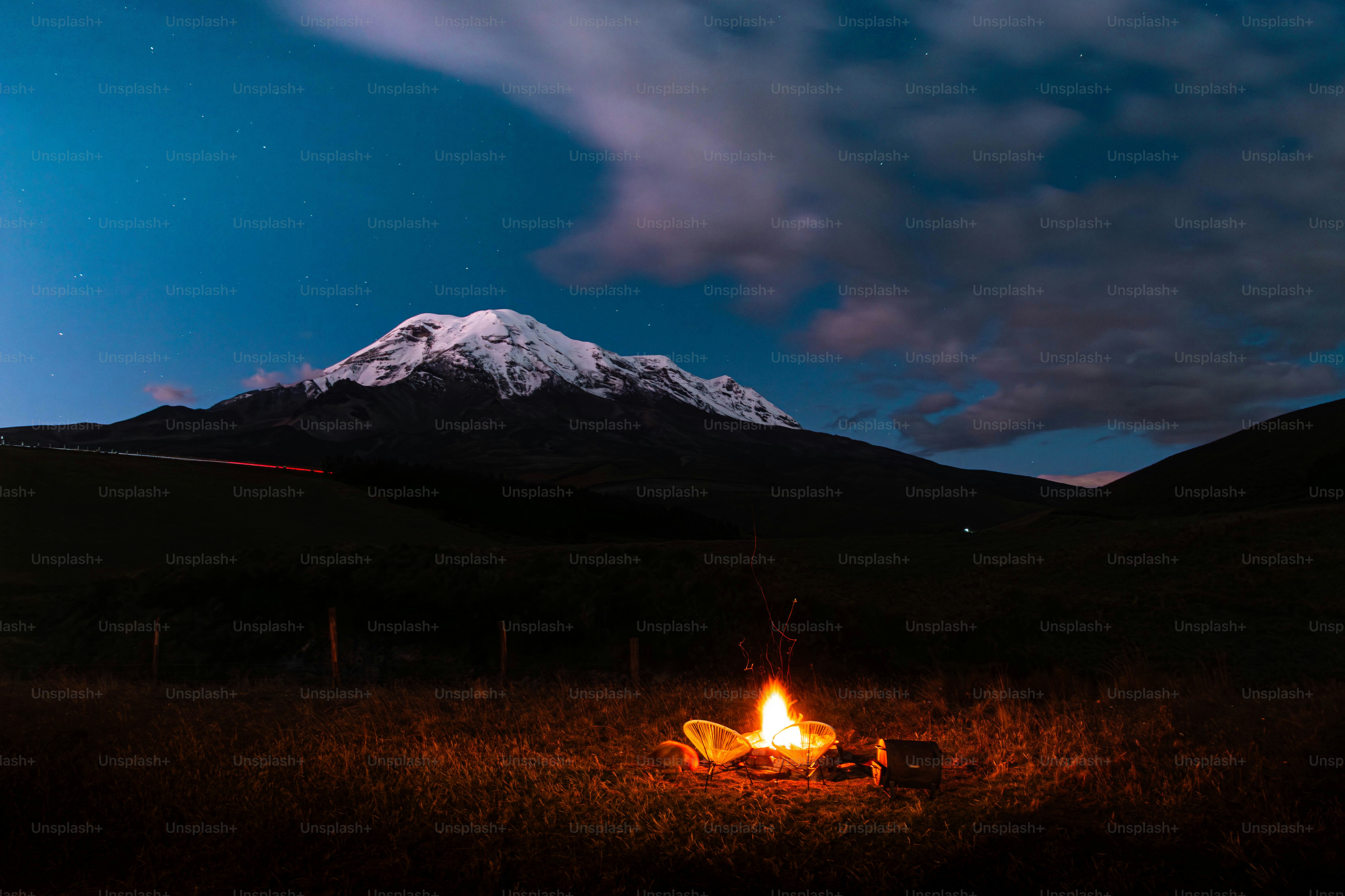 A campfire in a field with a mountain in the background photo – Ecuador ...