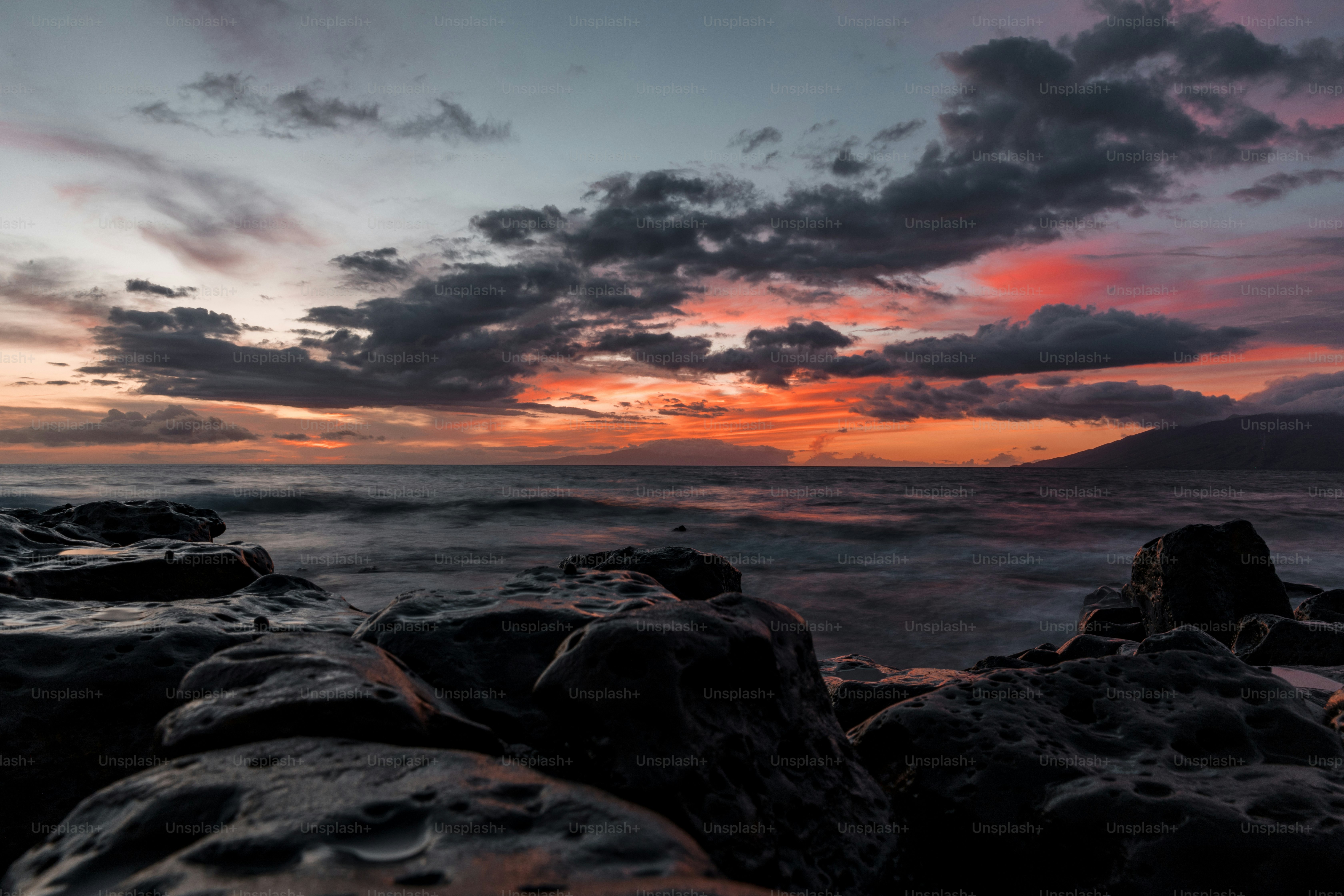 A sunset over the ocean with rocks and water photo – Scenery Image on ...