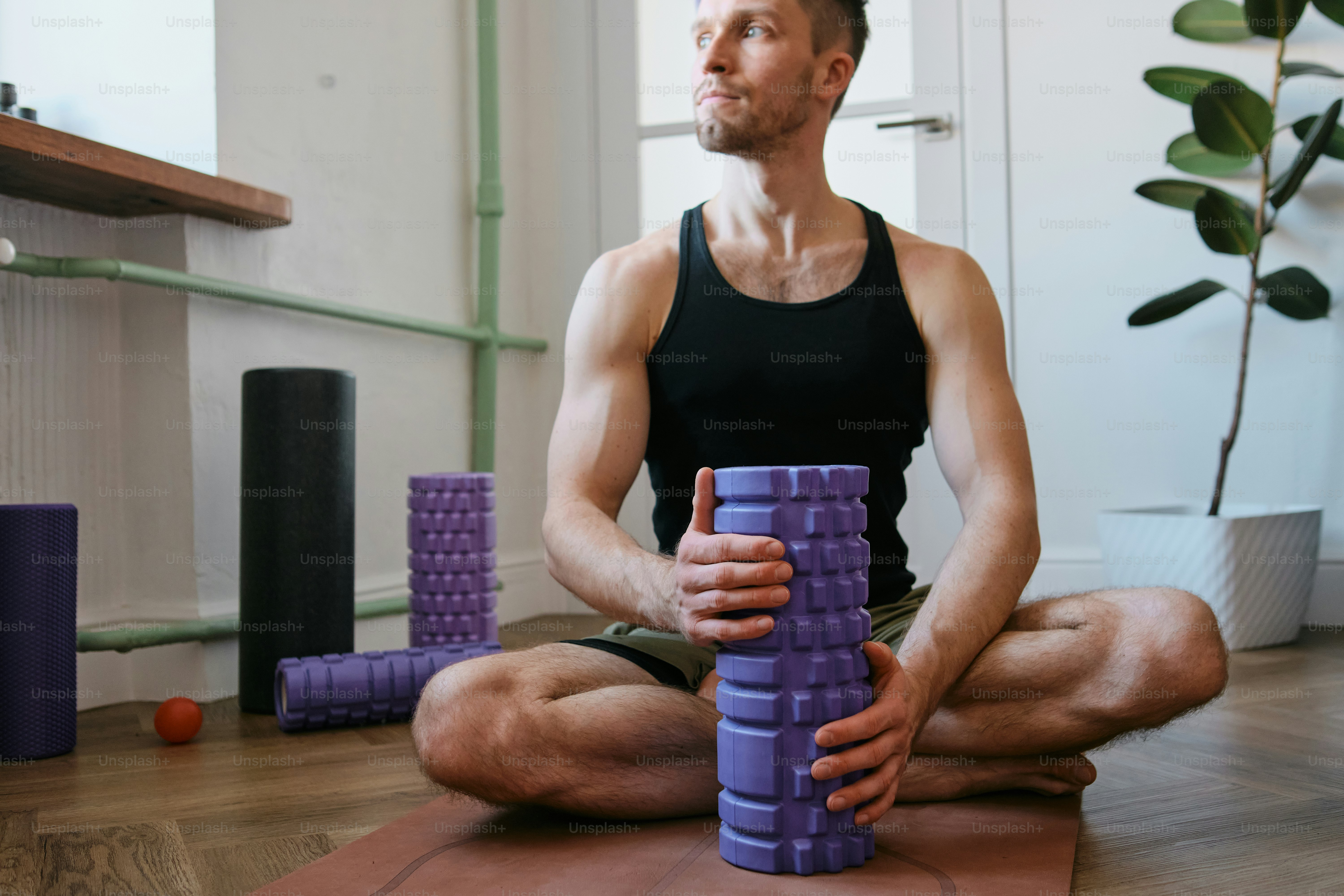 A man sitting on the floor with a stack of yoga mats photo – Fitness ...