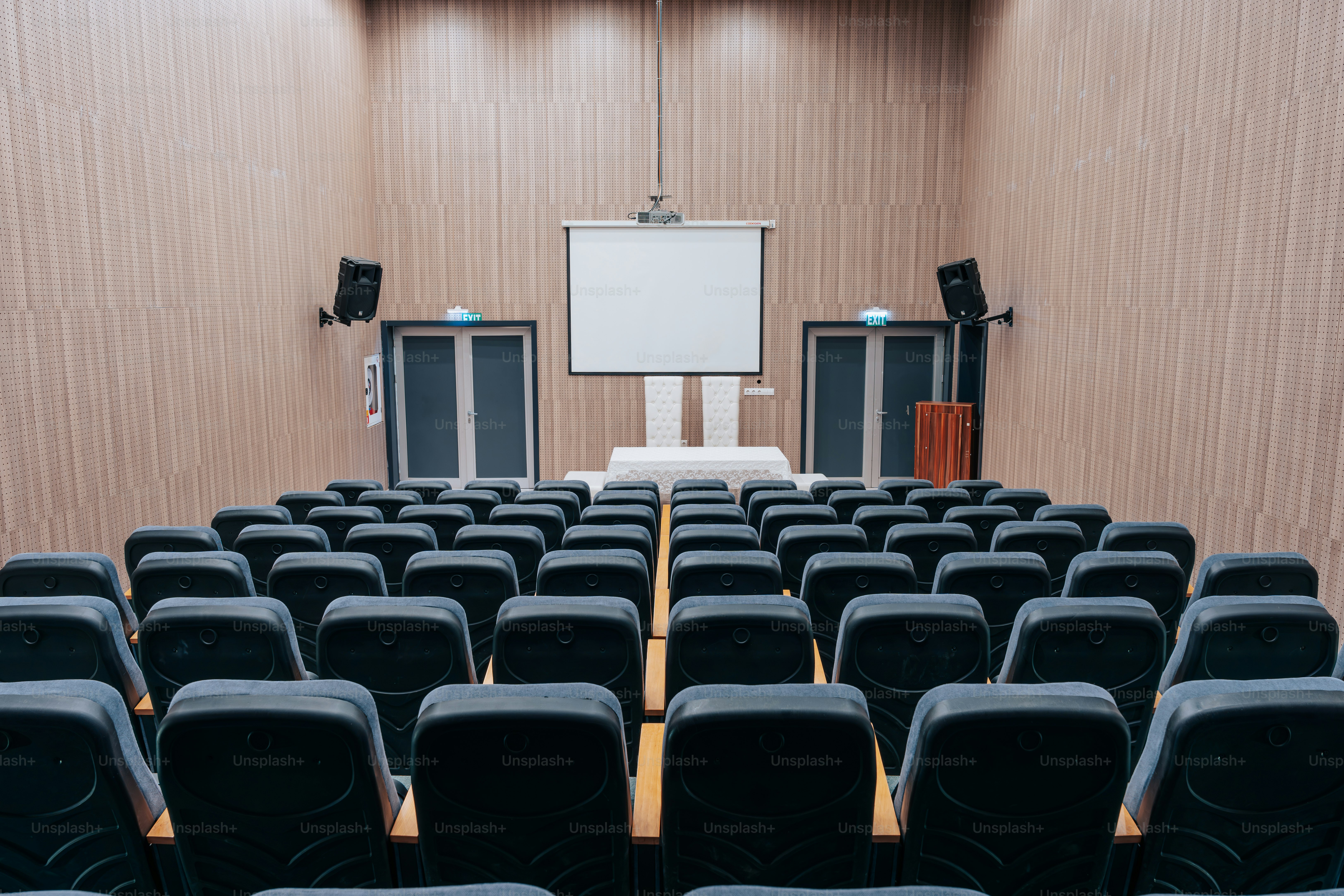 A large auditorium with rows of chairs and a projector screen photo ...