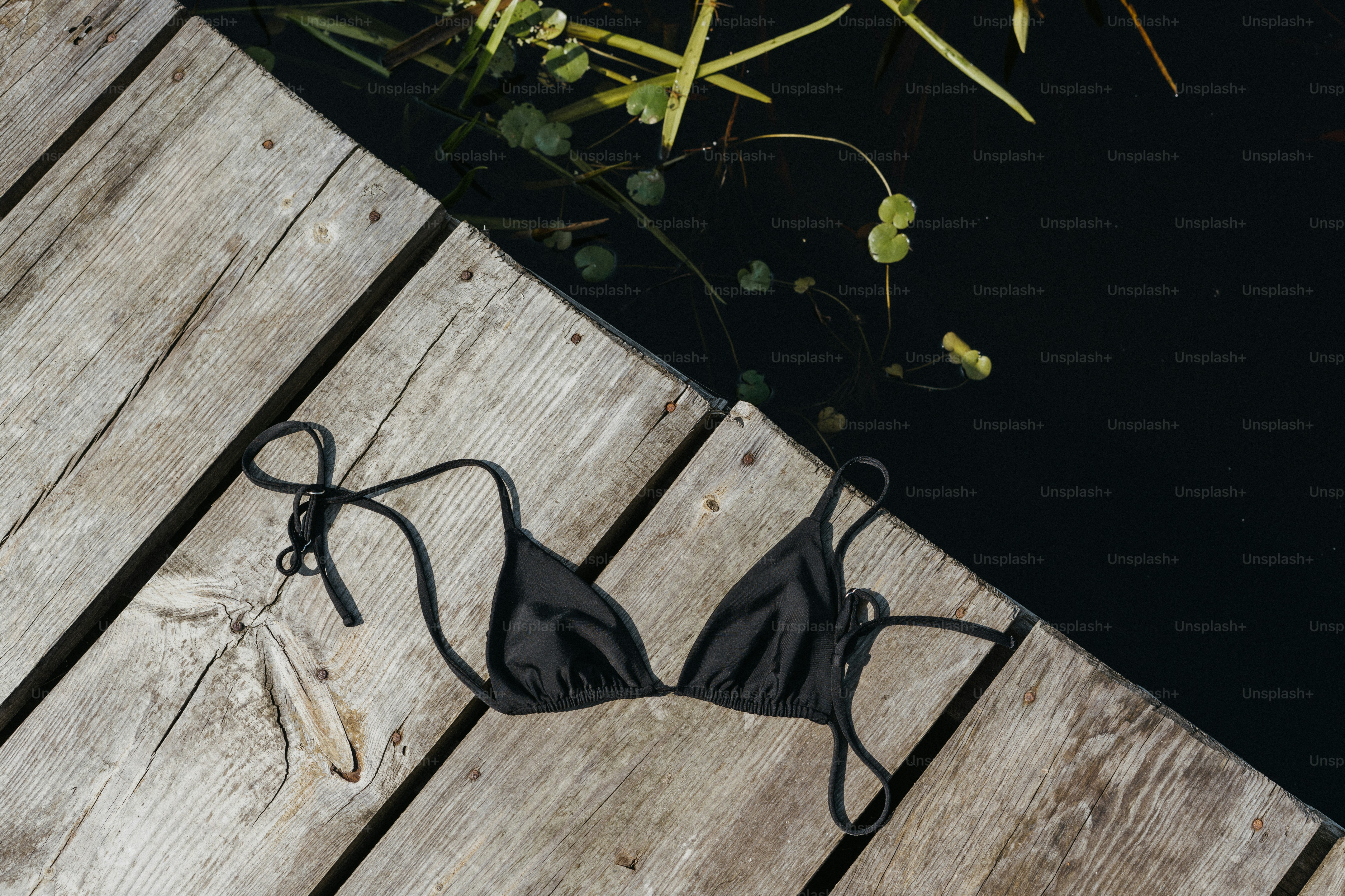 A pair of bikinis sitting on a wooden deck photo – Swimming suit Image ...