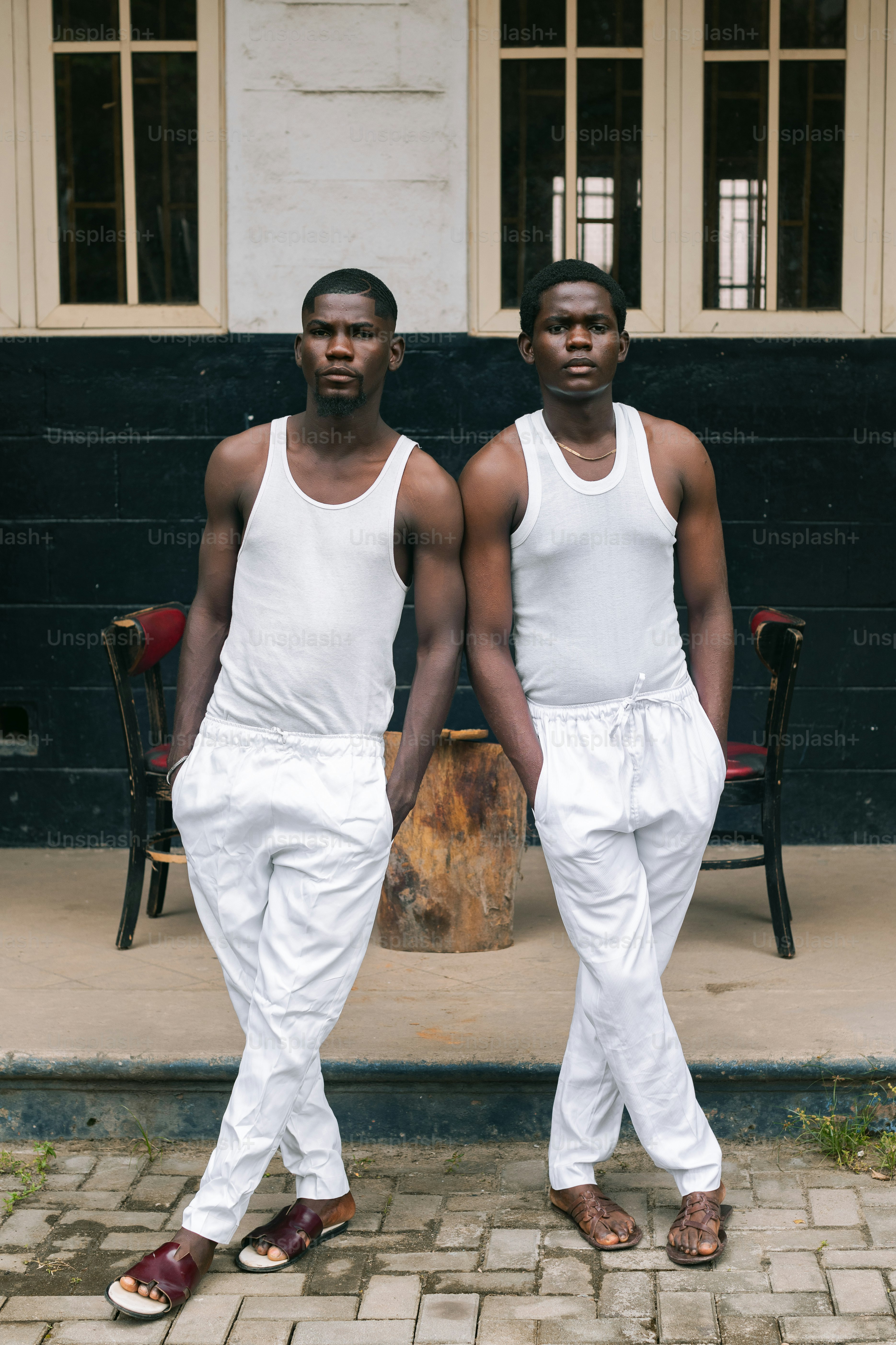 Two young men standing next to each other in front of a building photo ...