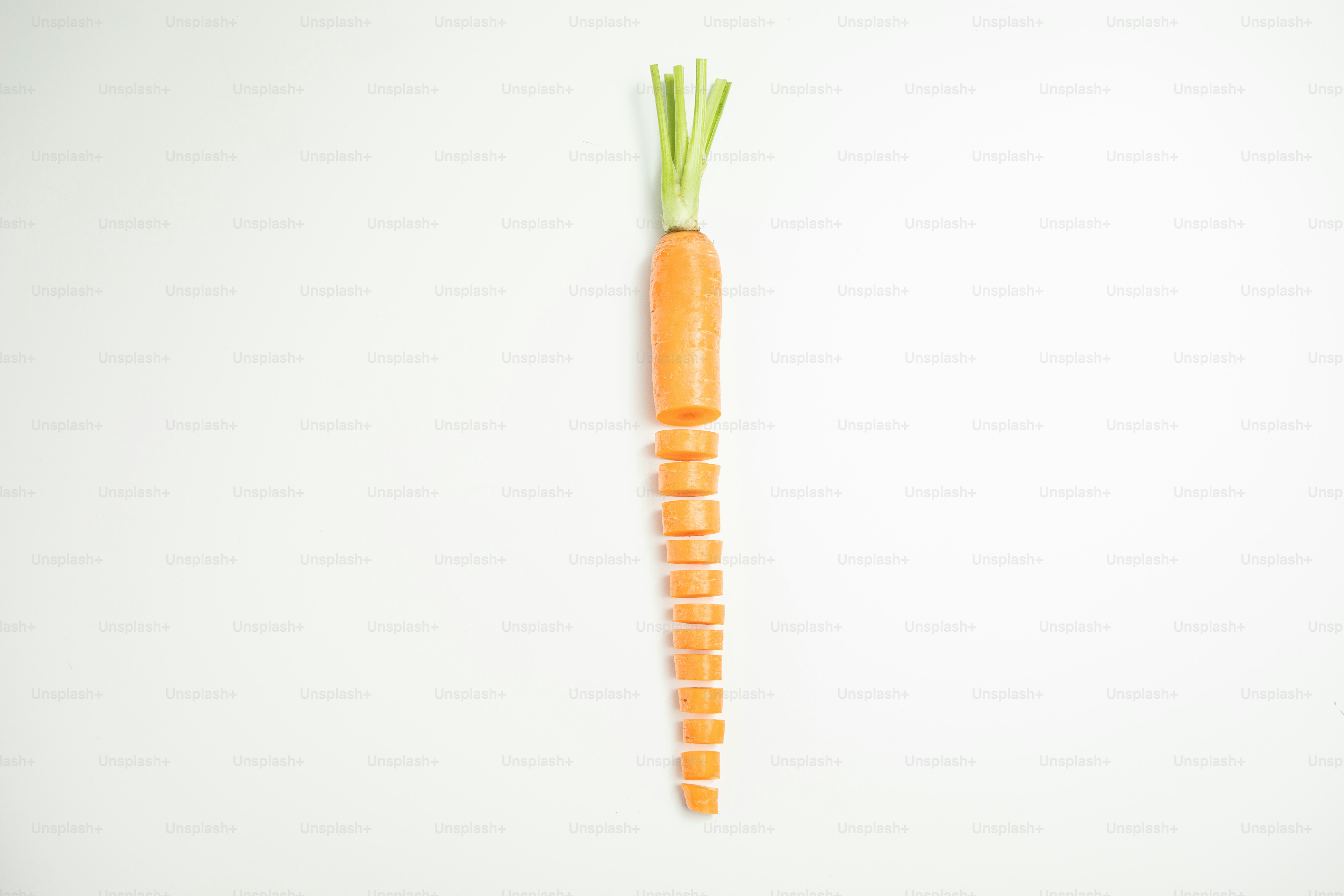 A single carrot sitting on top of a white table photo – Vegetable Image ...