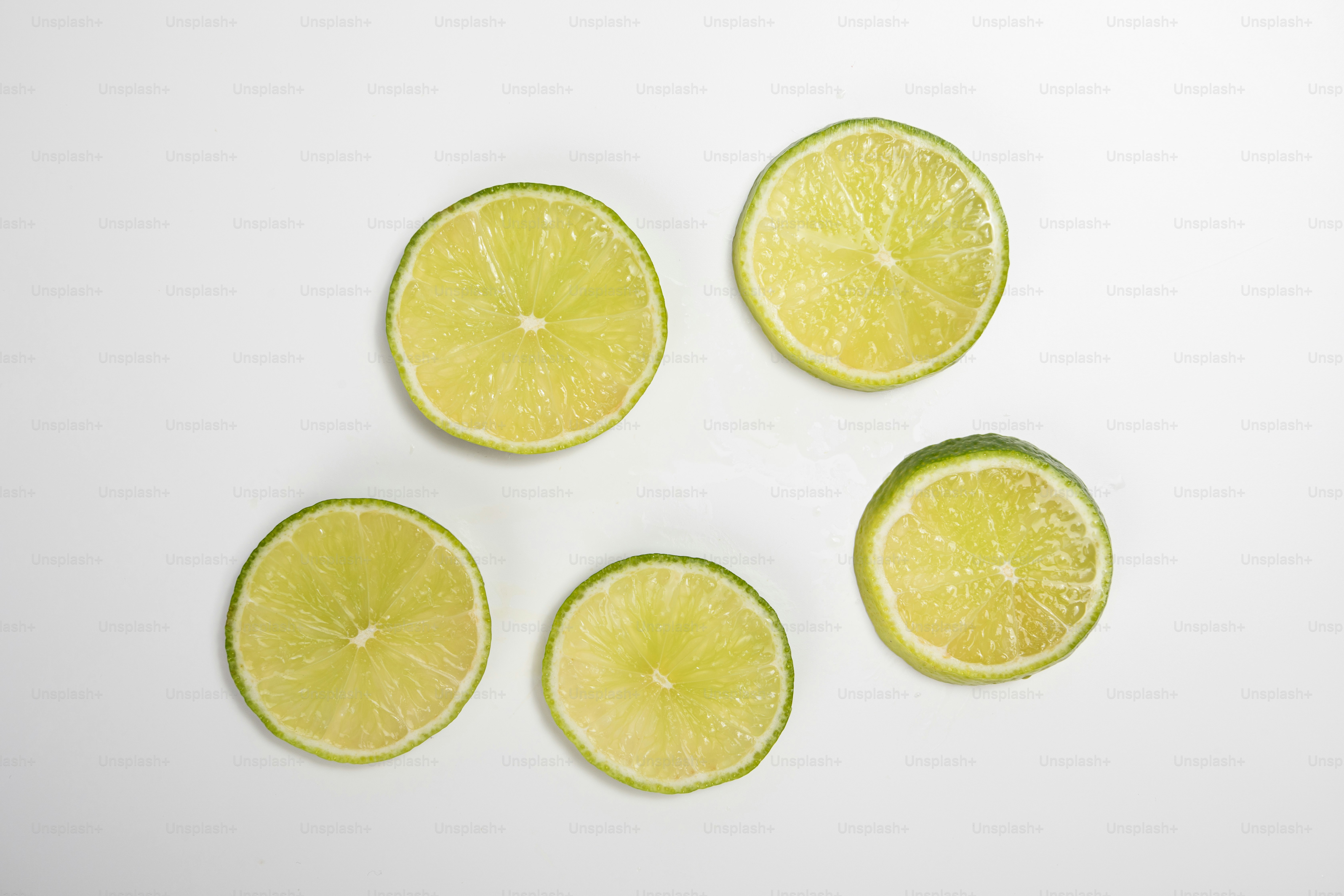 A group of limes sitting on top of a white table photo – Lime slice ...