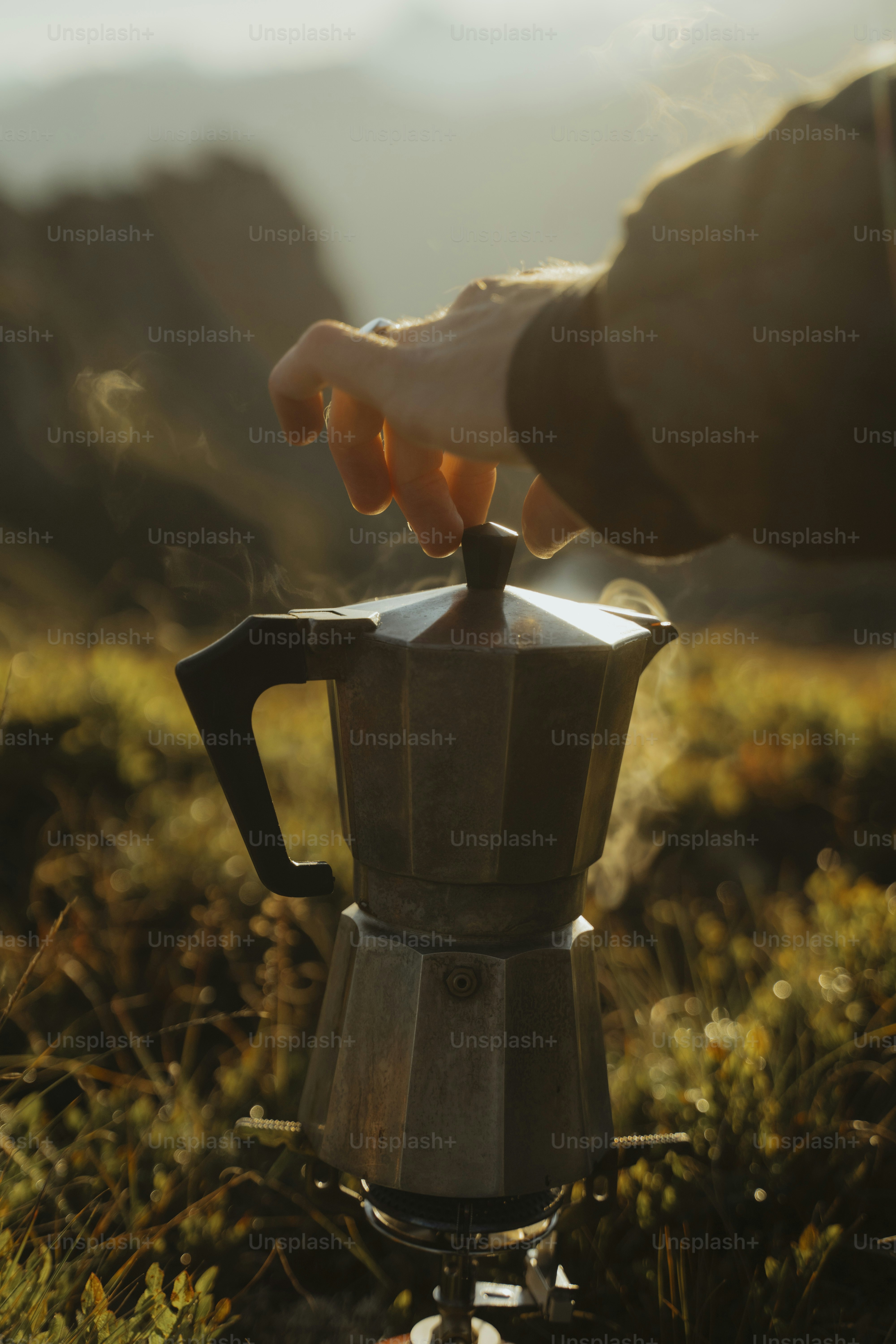 A person is putting something in a coffee pot photo – Alps Image on ...