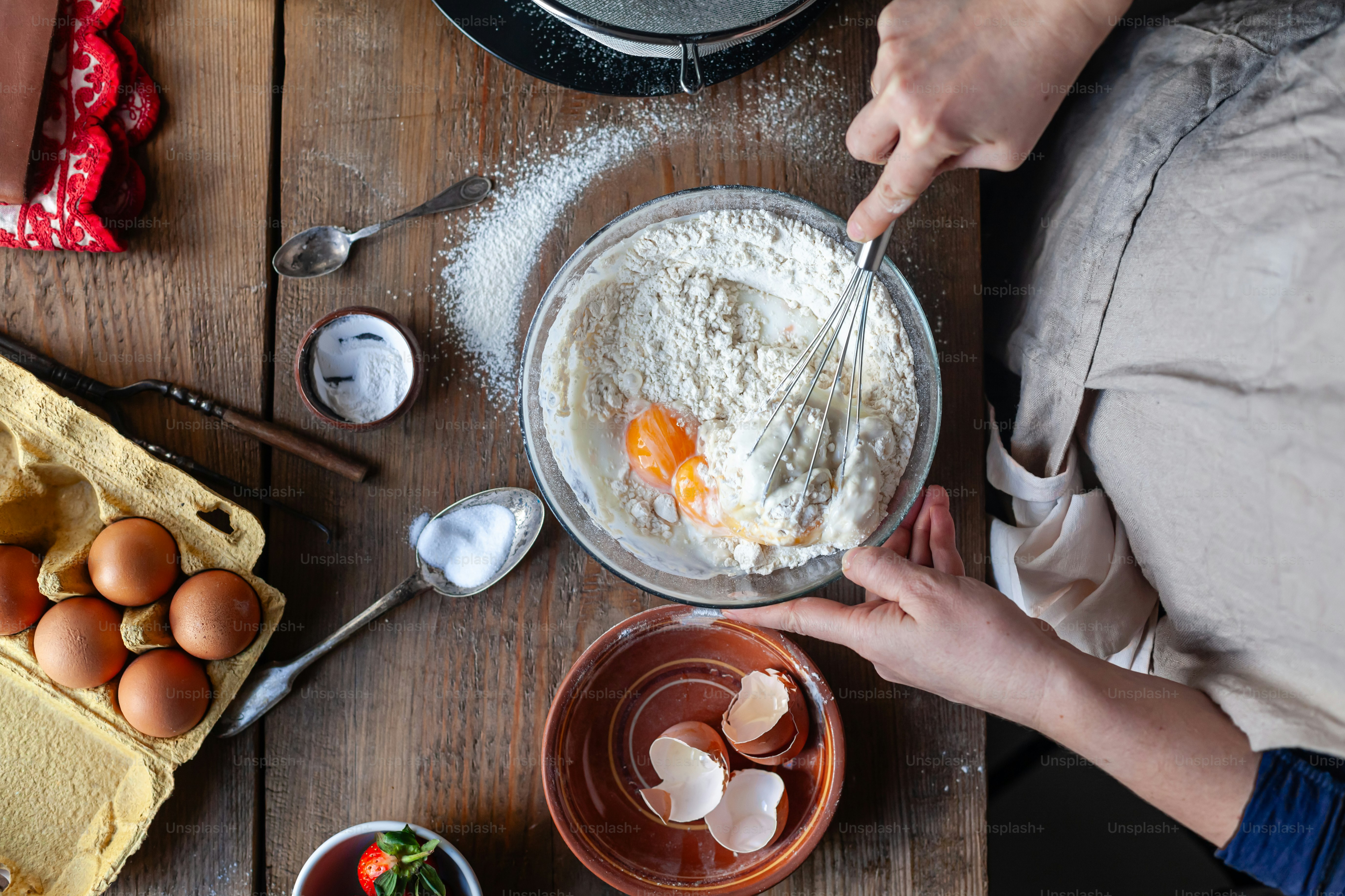 A person mixing ingredients in a bowl on a table photo – Dough Image on ...