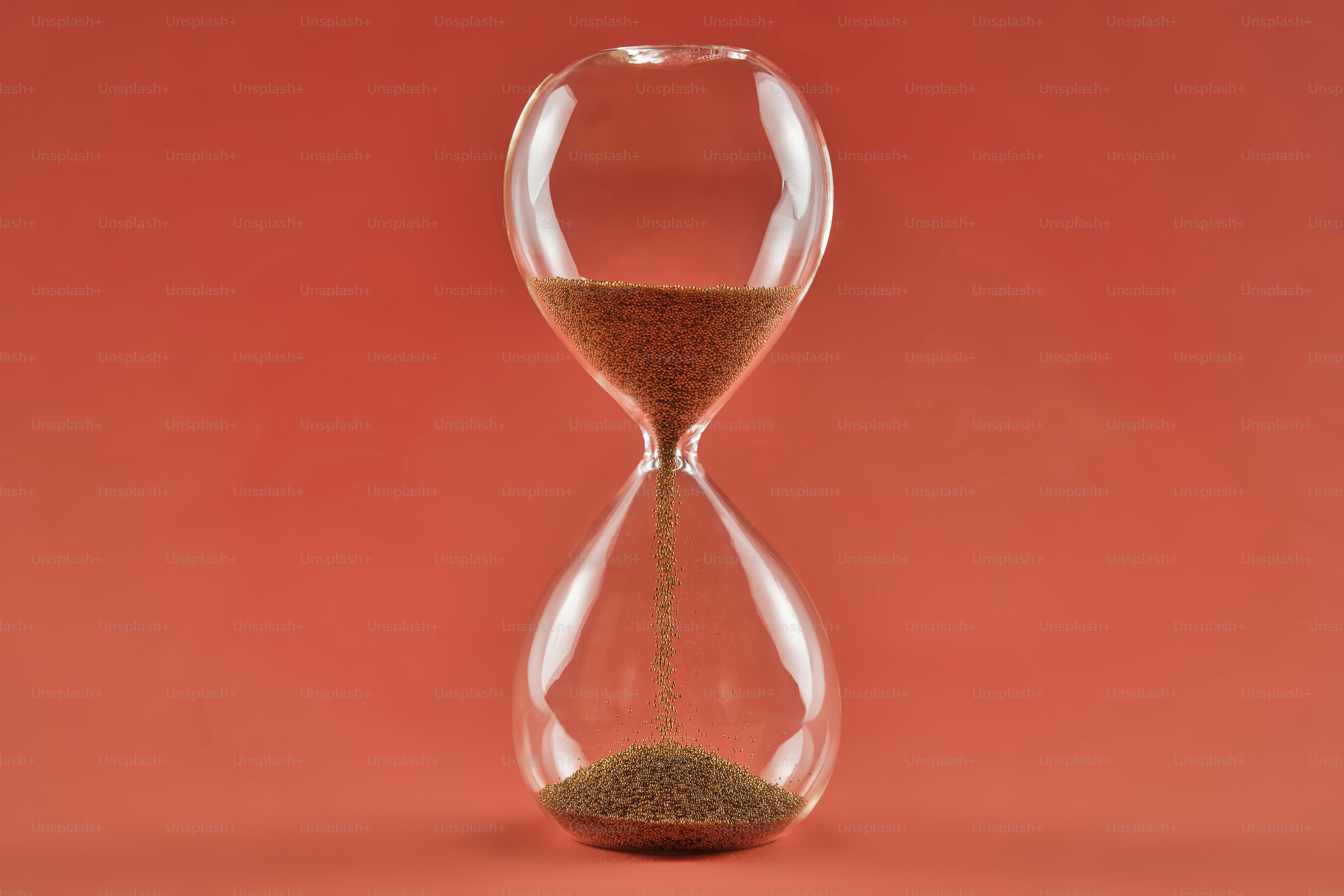 An hourglass with sand in it on a pink background photo – Hourglass ...