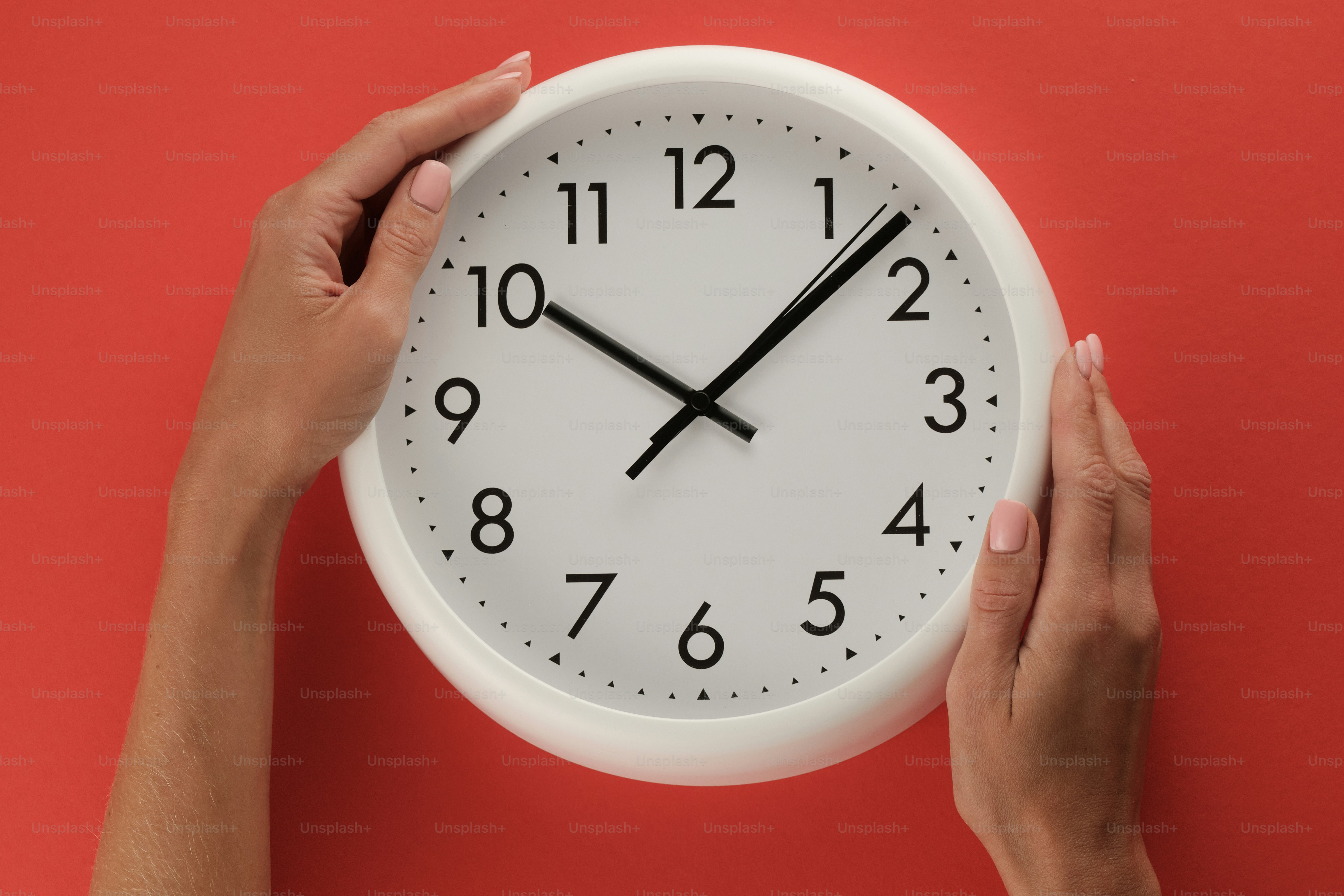 A person holding a clock on a red wall photo – Clock Image on Unsplash