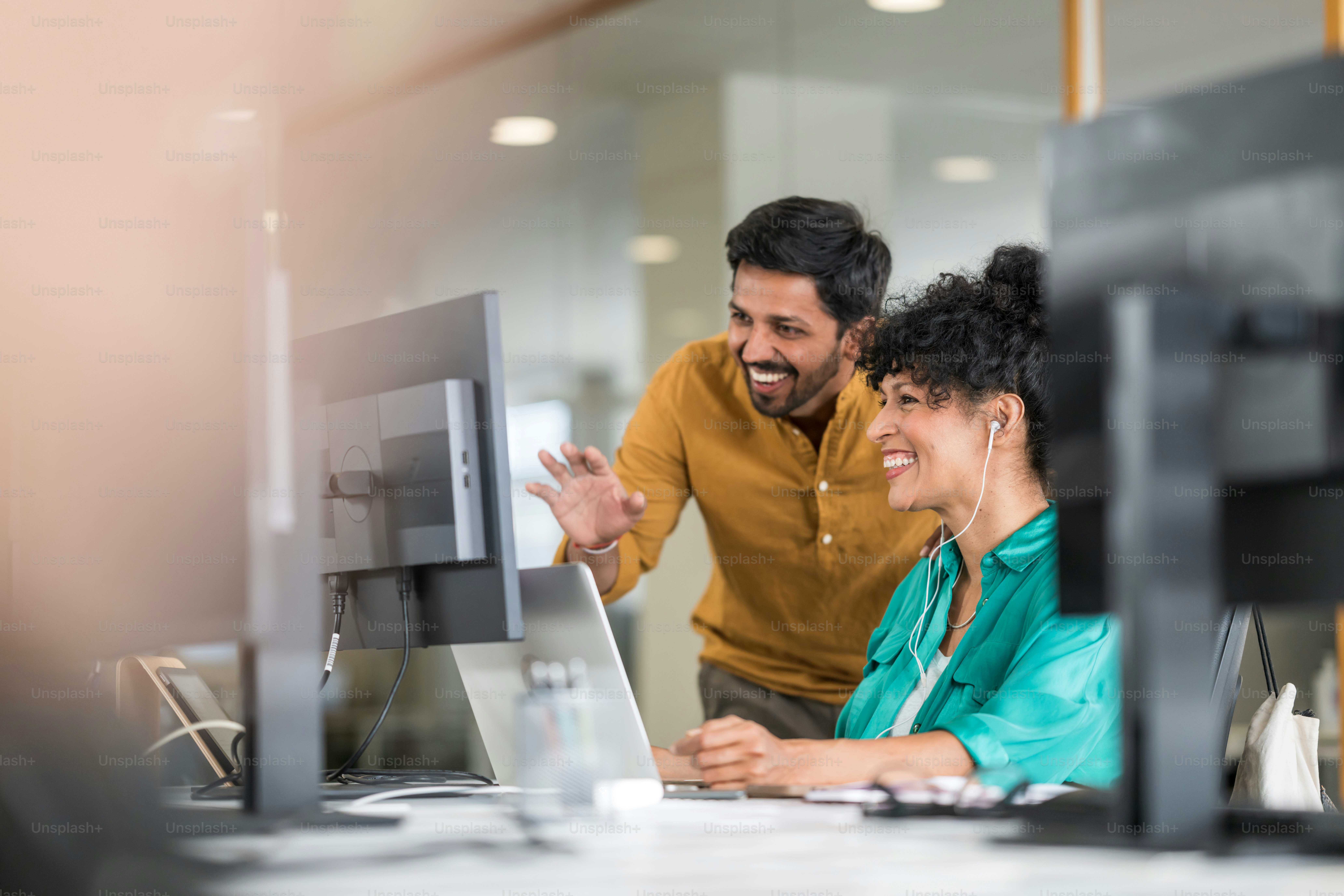 Coworkers in front of computer monitor in modern office chatting online ...