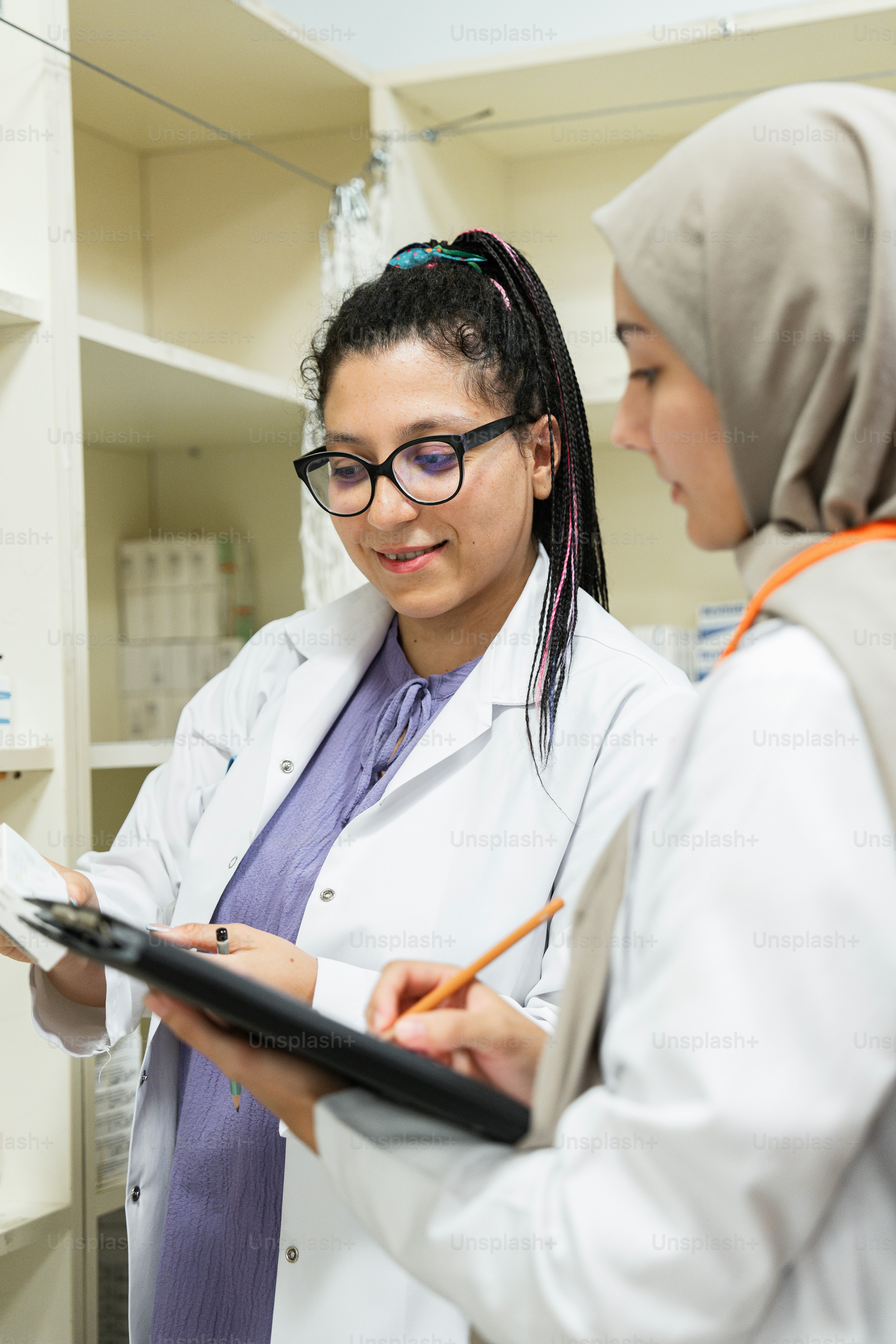 Two women in lab coats looking at a clipboard photo – Mentoring Image ...