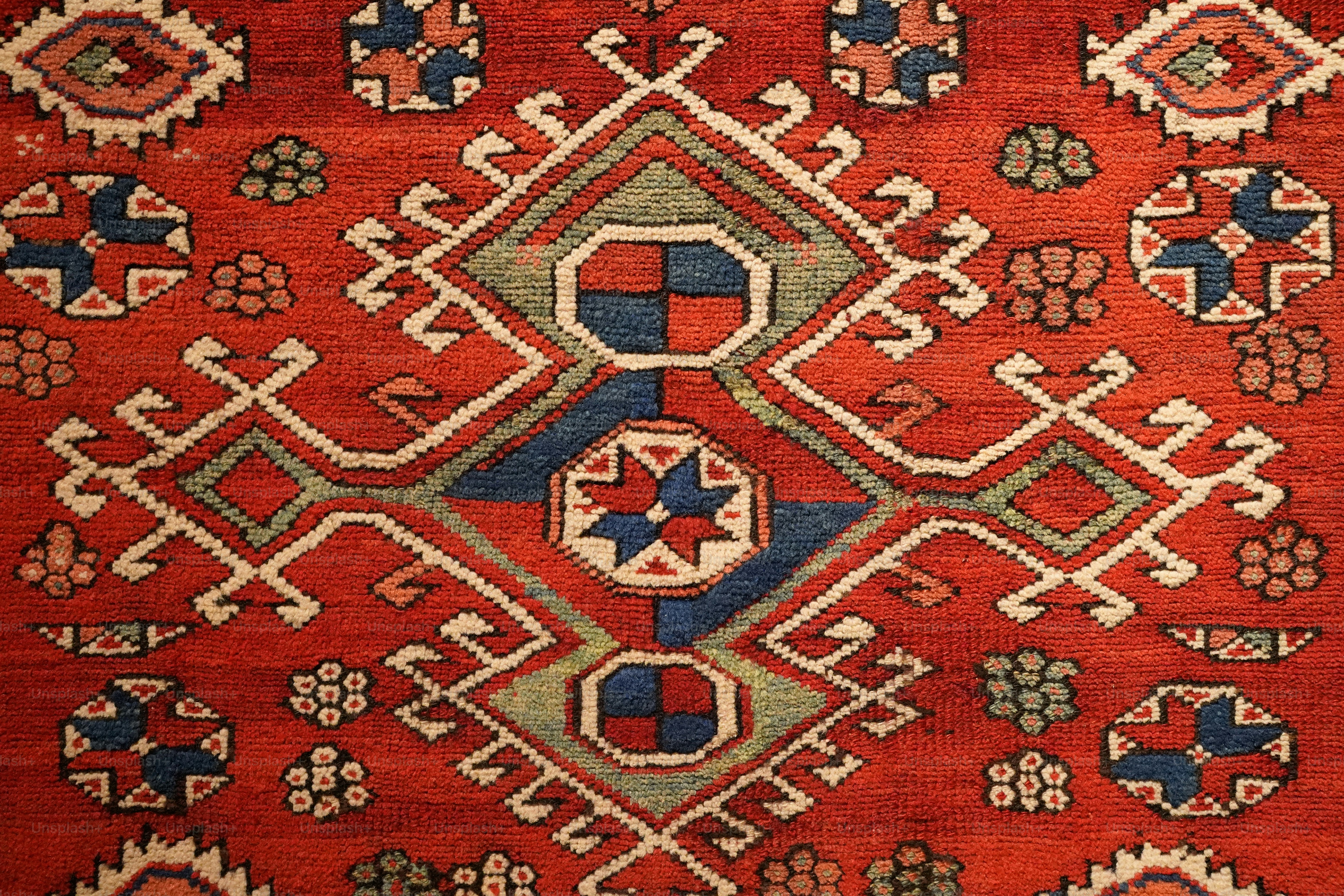 A close up of a red rug with blue and green designs photo – Pattern ...