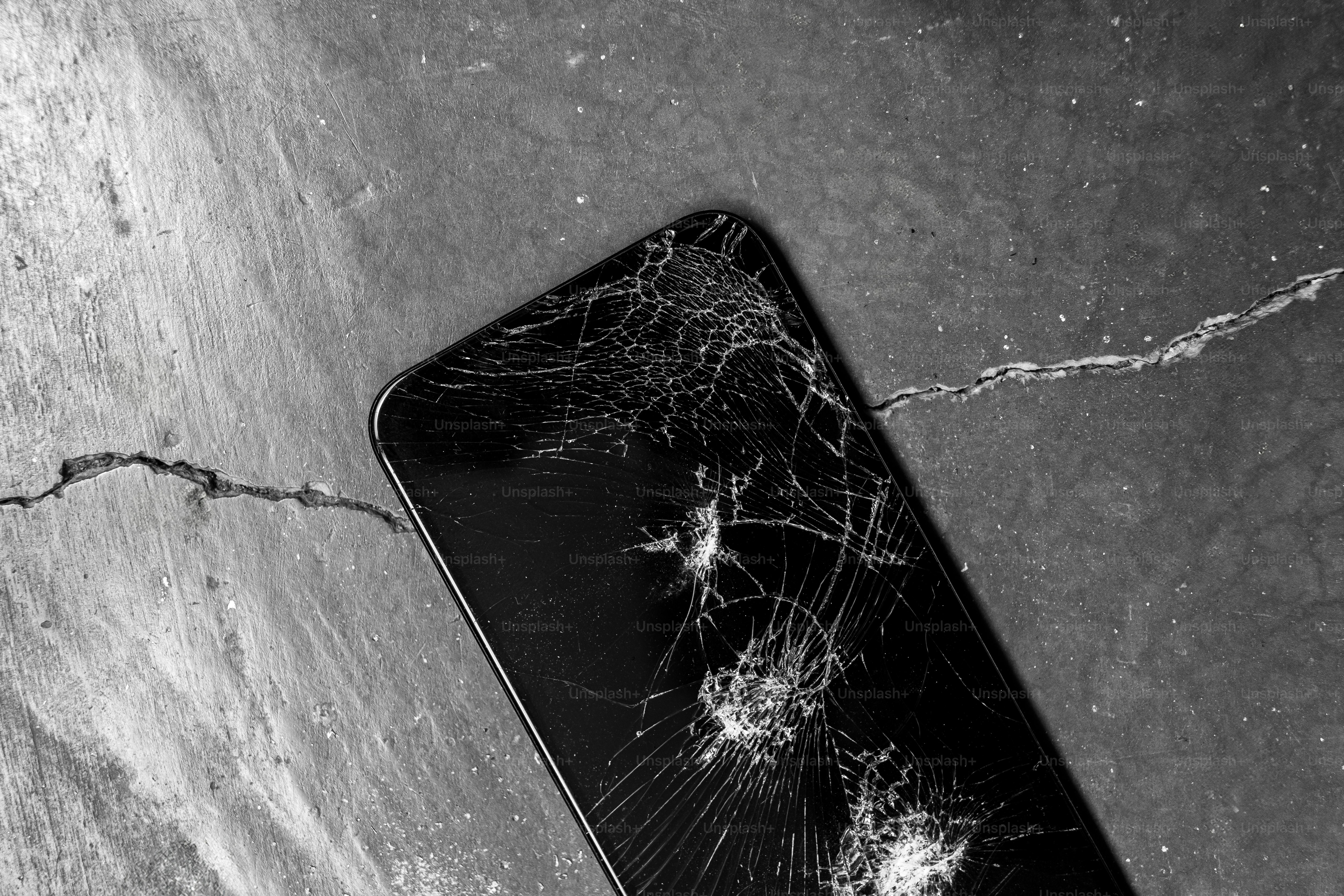 Un teléfono celular roto encima de una mesa foto – Imagen de ...