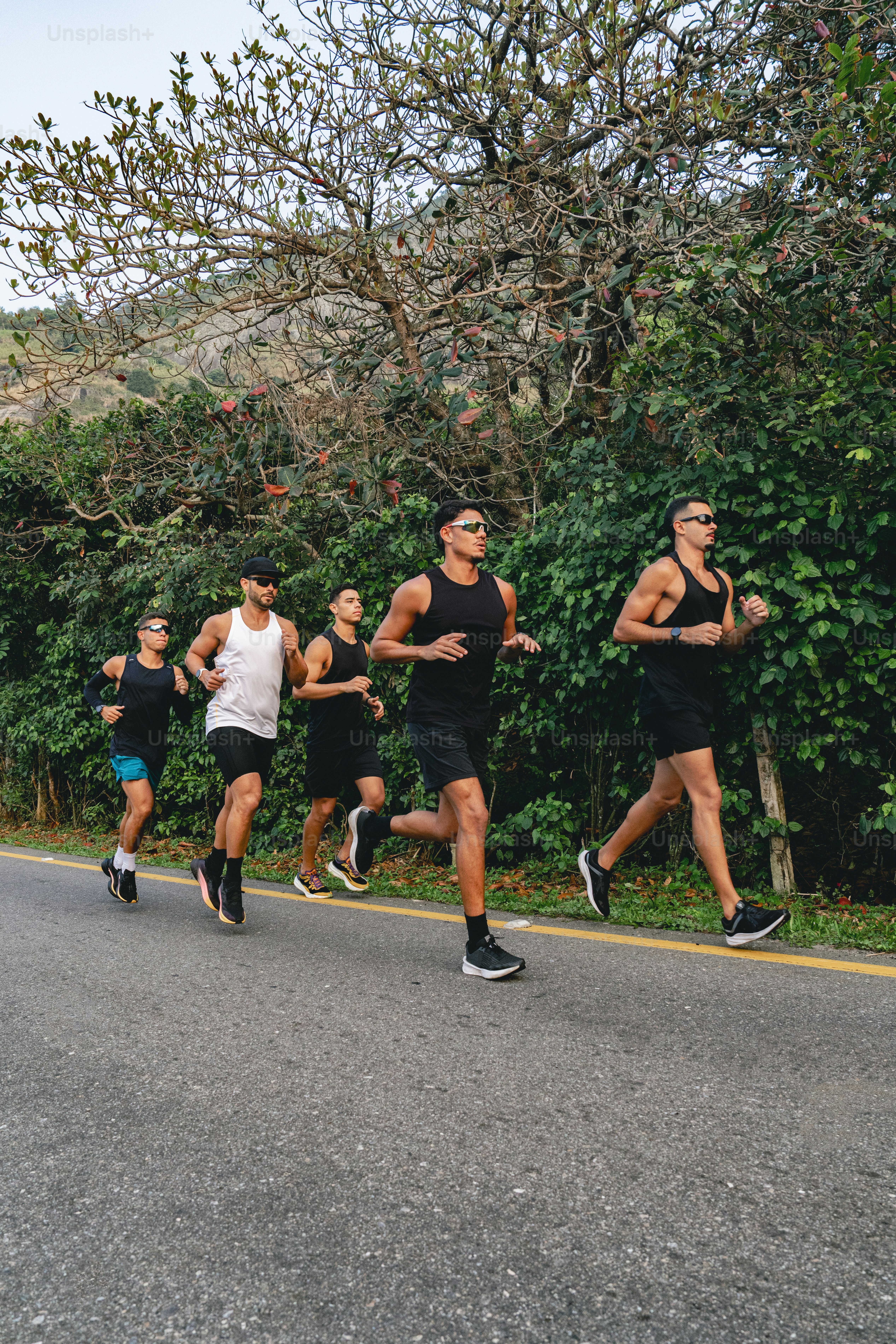A group of men running down a road photo – Runners Image on Unsplash
