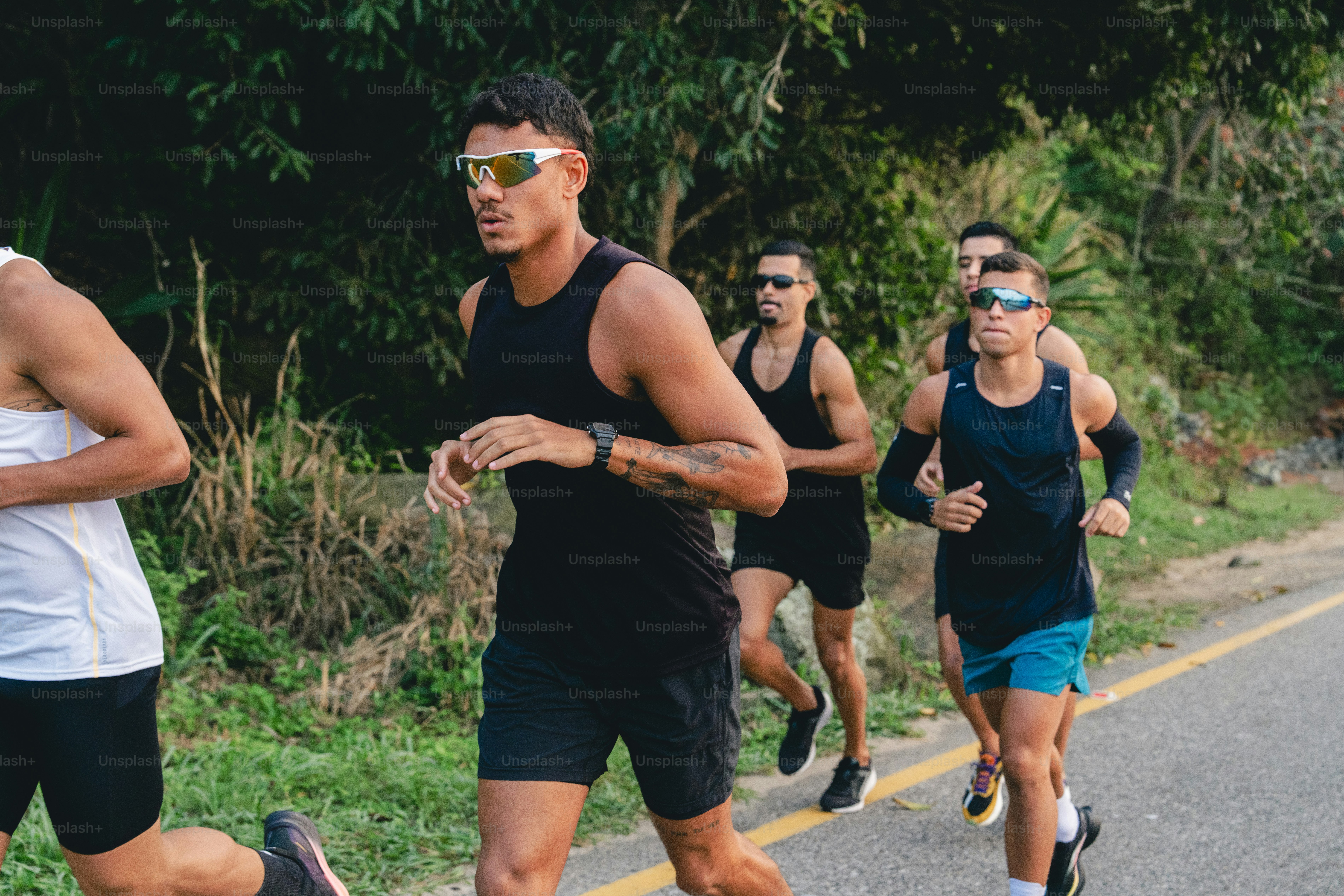 A group of men running down a road photo – Running Image on Unsplash